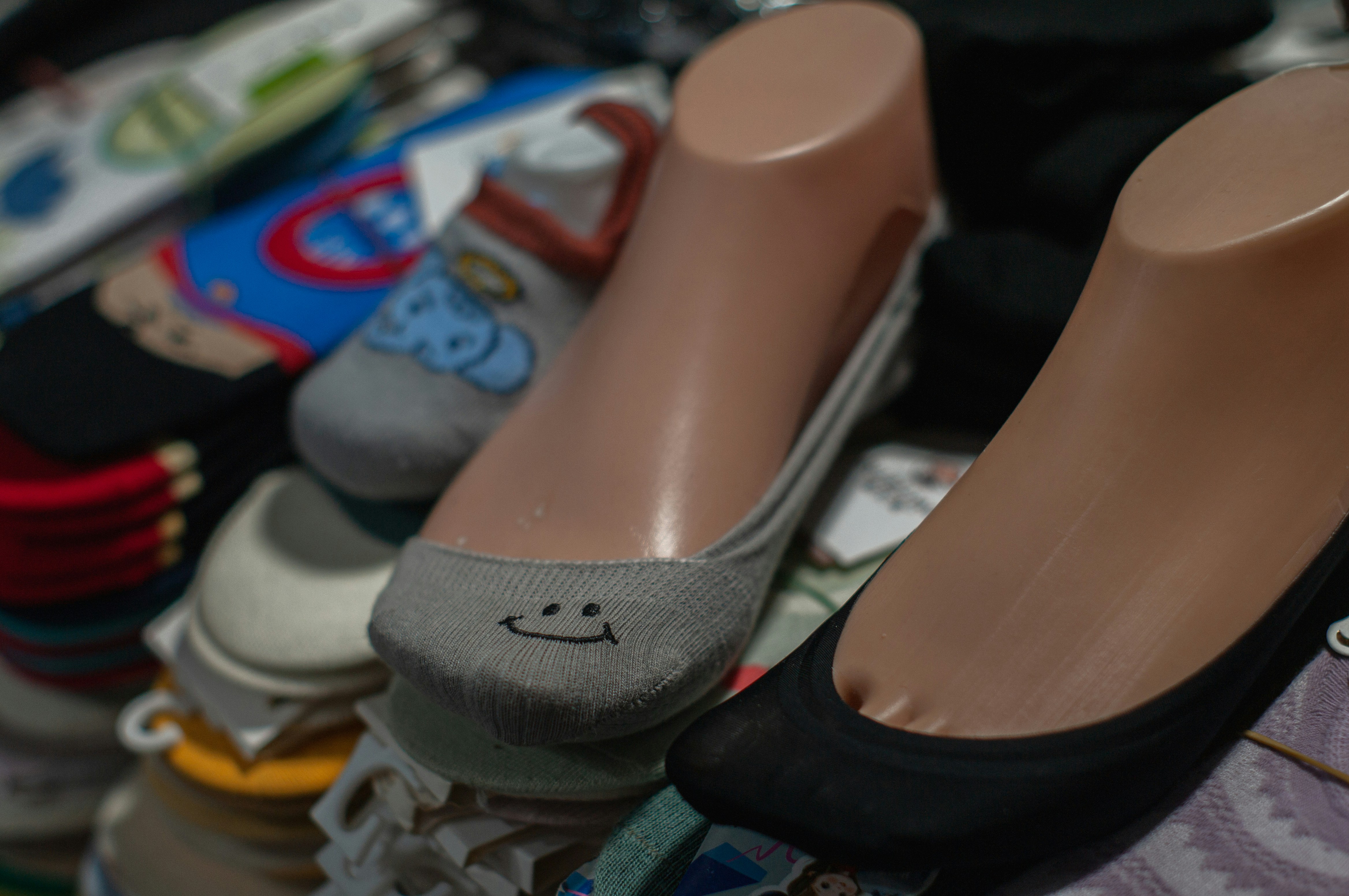 A collection of colorful socks displayed on a table, featuring a smiling face design on one pair. The assortment highlights playful and casual styles.