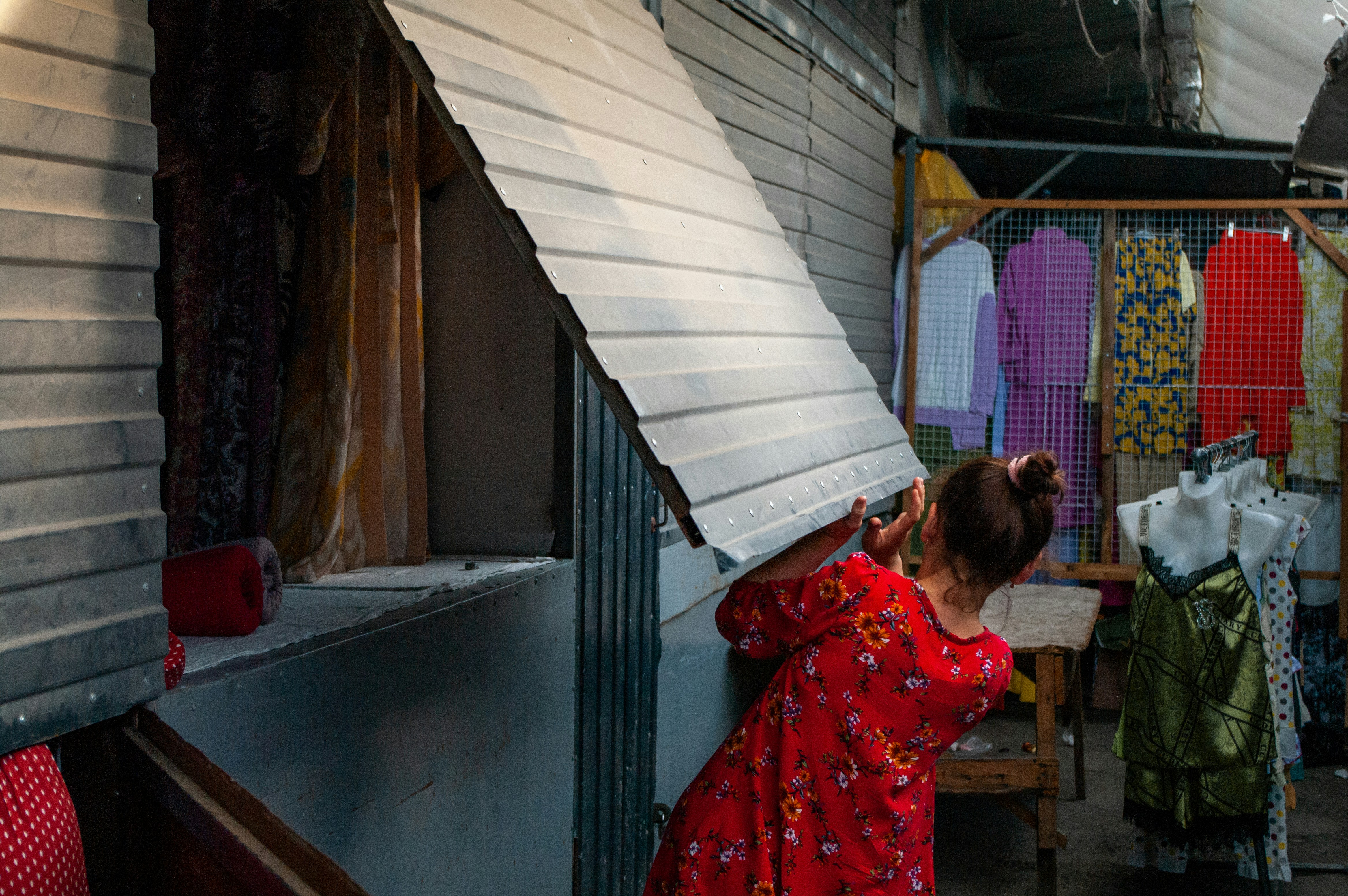 Woman opens a shop shutter to begin the day. photo – Free Woman Image ...