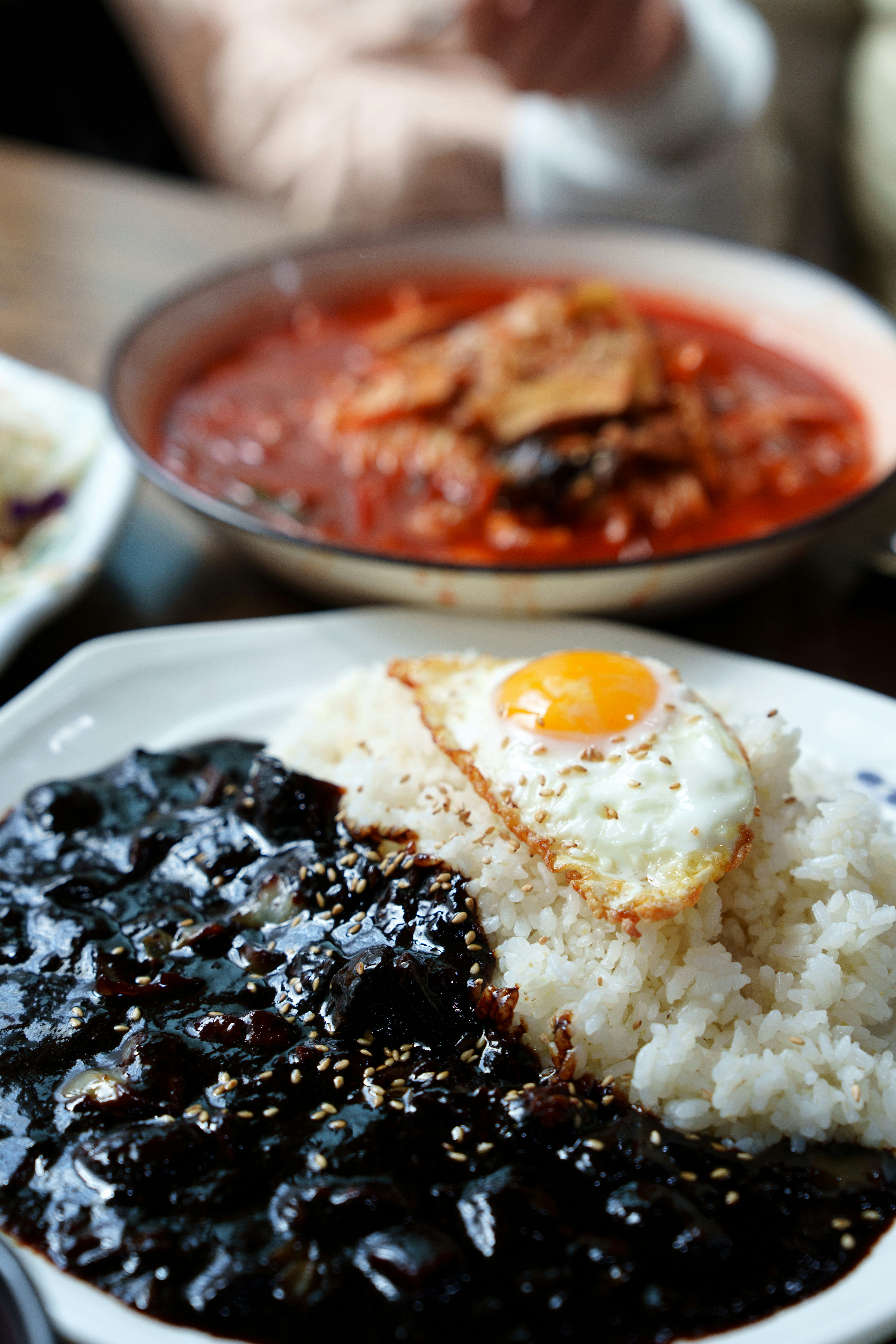 Sunny Egg on Glossy Black Rice with a Fiery Red Broth Backdrop