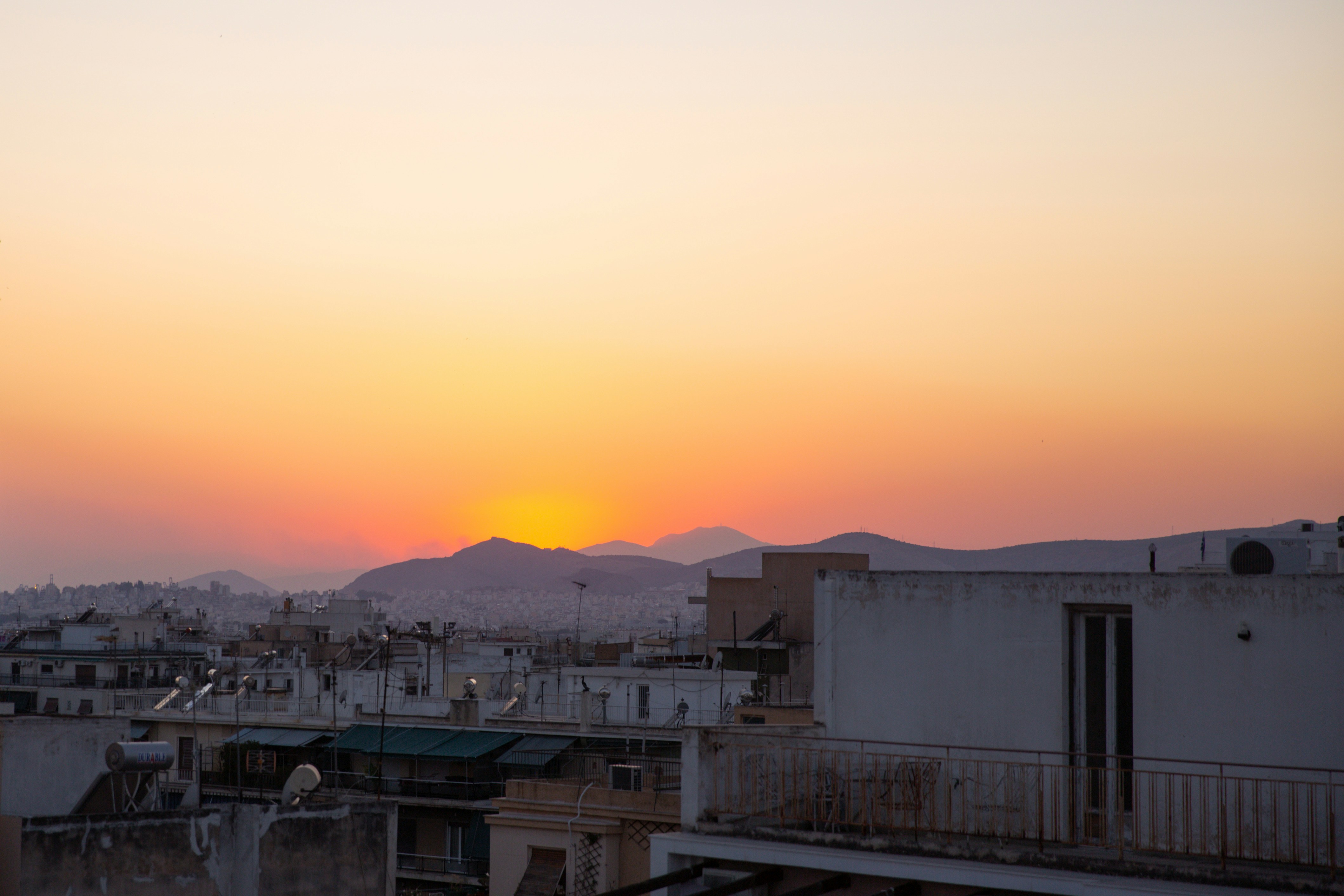 Sunset casting a warm glow over a cityscape with mountains in the background.