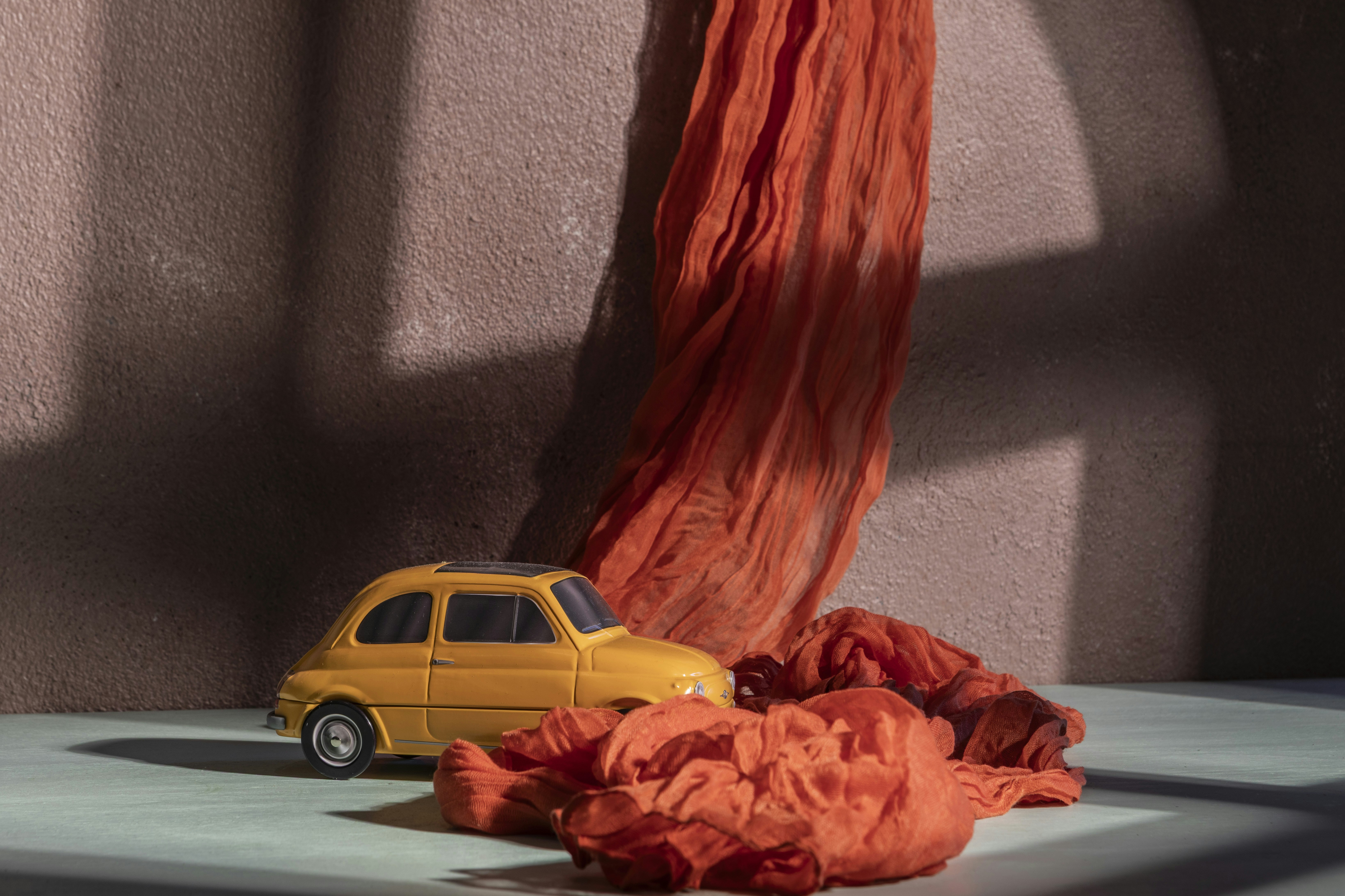 Sunlit Miniature Car Among Crimson Drapery