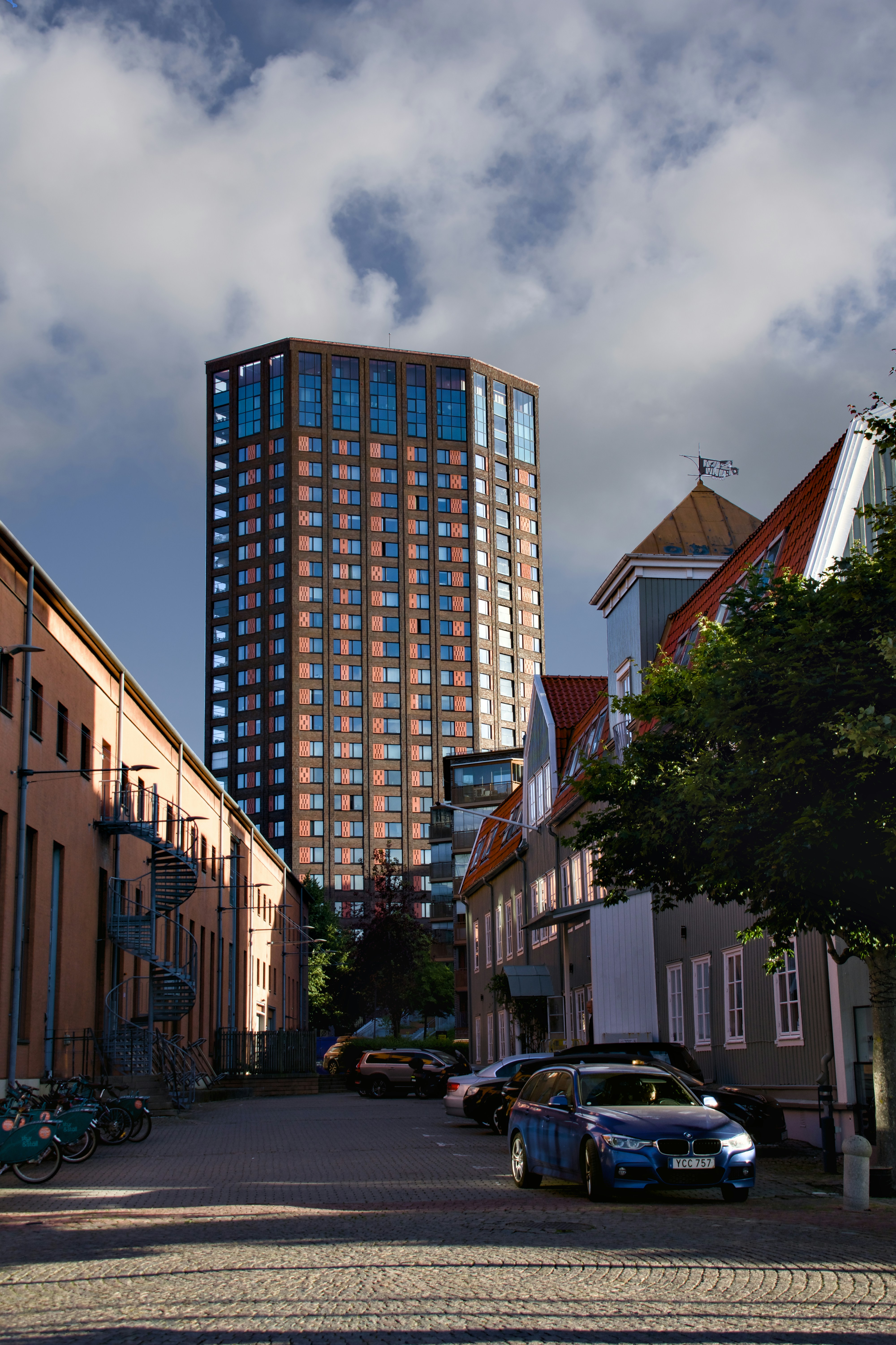 Skybound Brick: a slender urban tower watching over a sunlit street