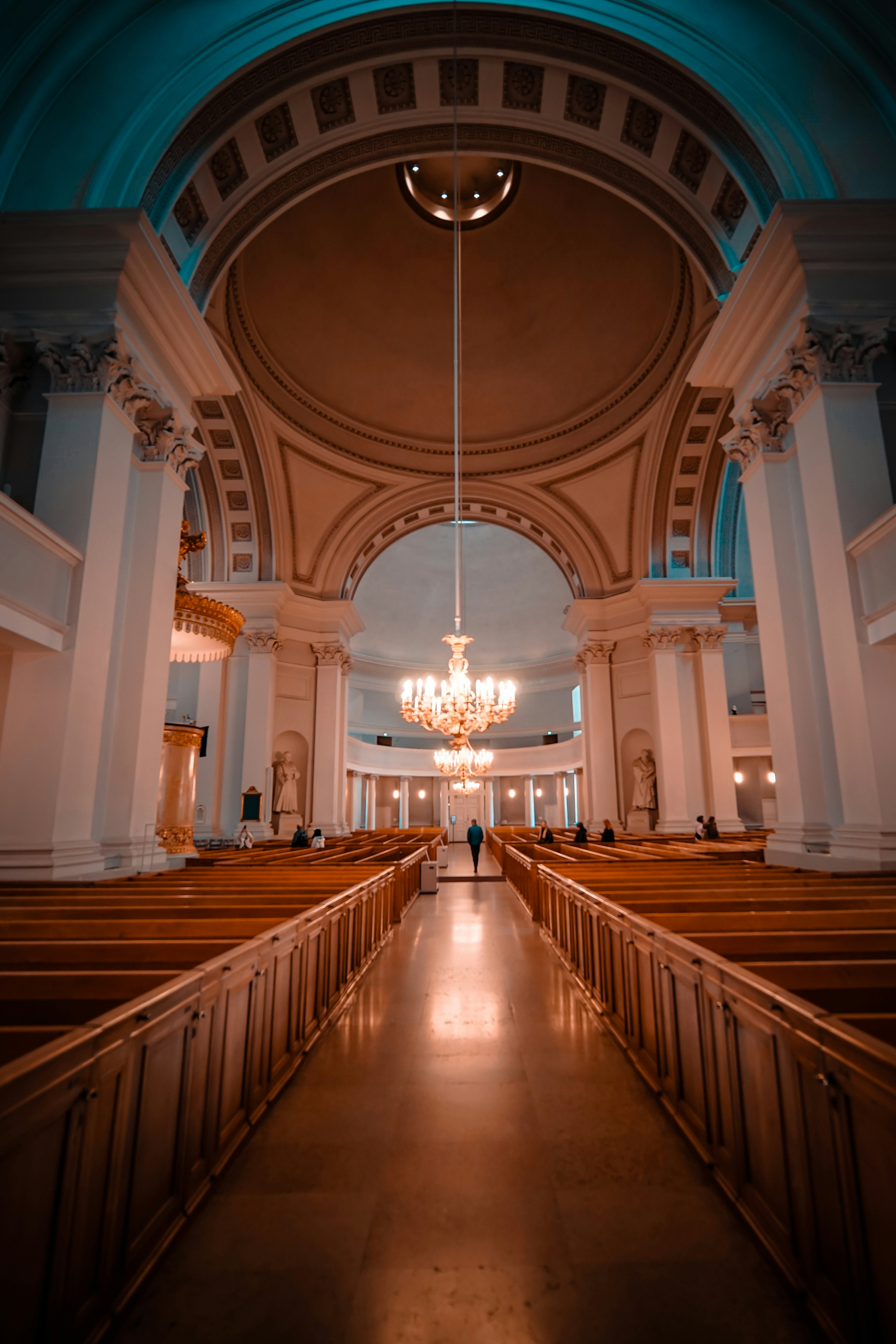 Ornate church interior with grand chandelier and towering columns bathed in warm light.