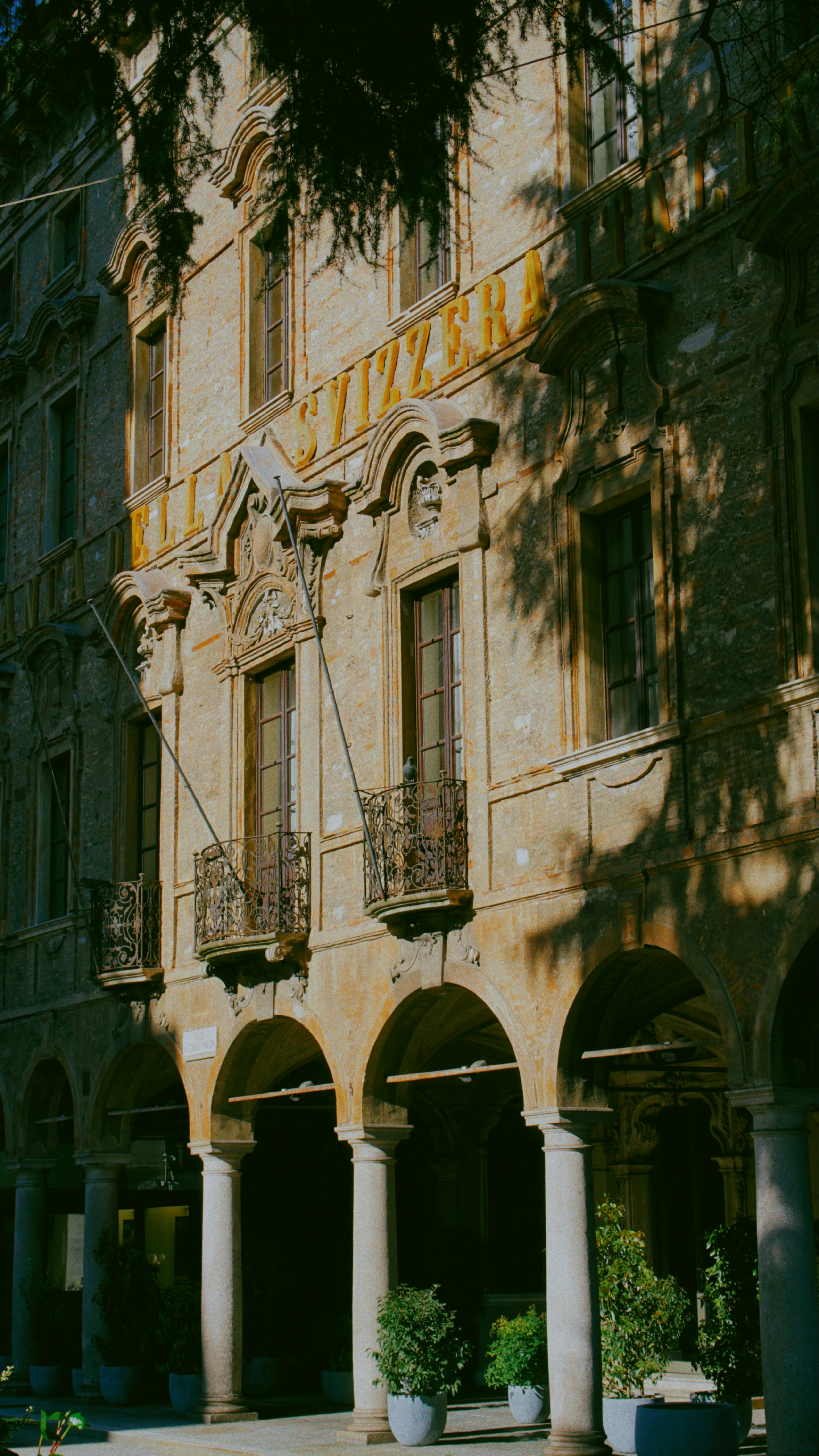 Ornate stone building with arched windows and balconies bathed in warm sunlight.