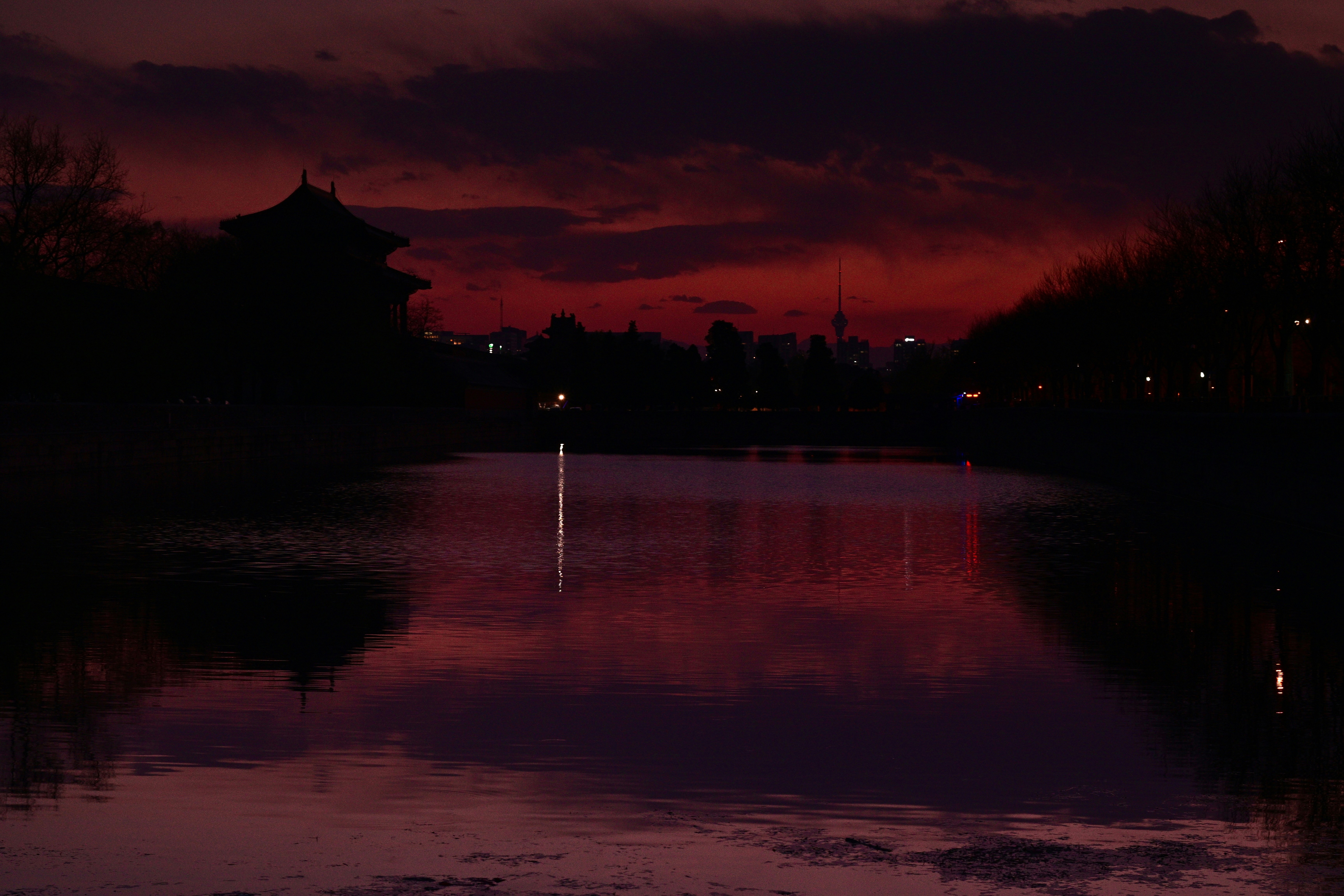 Crimson Reflections: Silhouette of a Pavilion at Dusk over a Quiet River