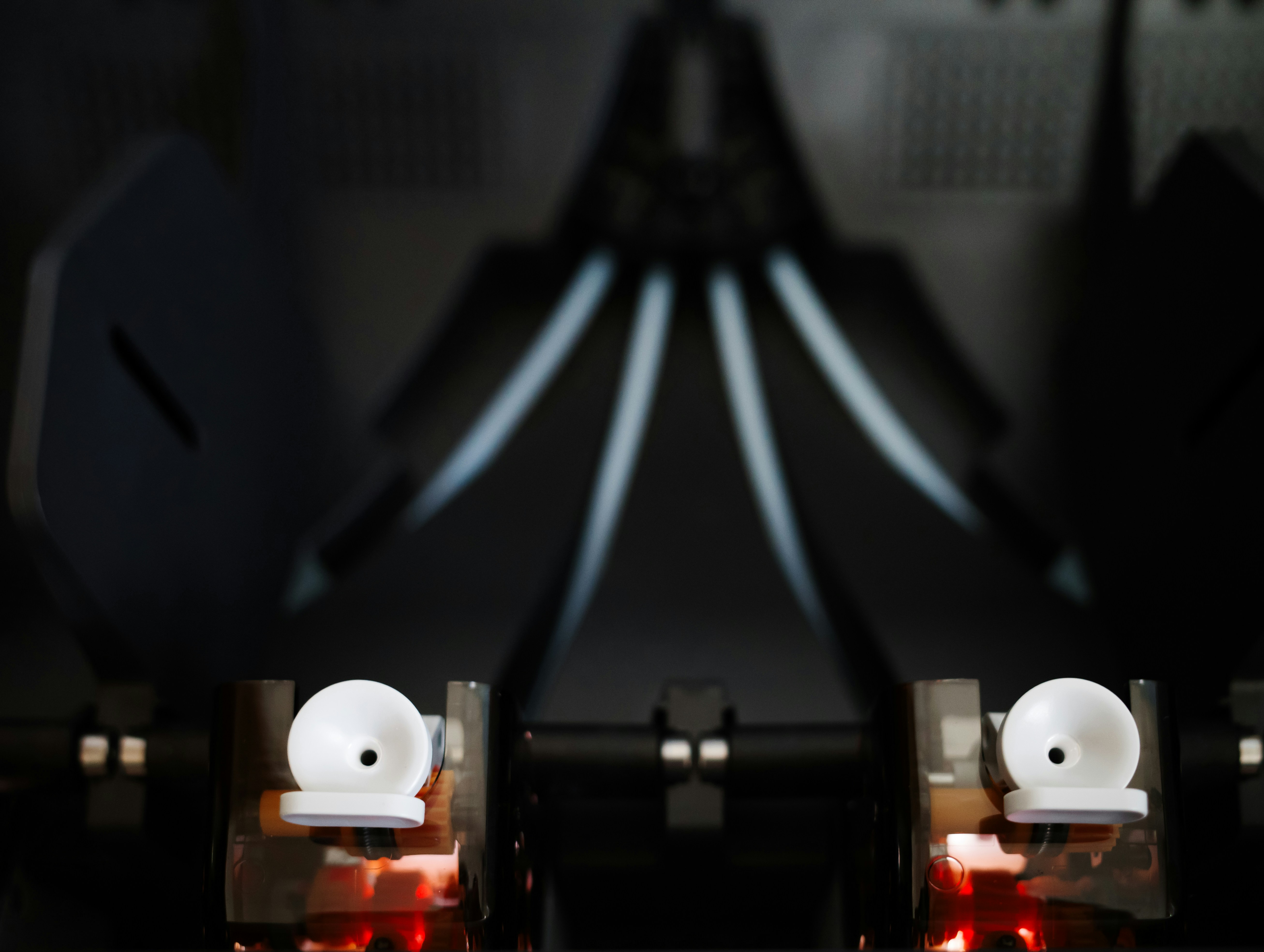 Two white components positioned symmetrically in a dark industrial setting, illuminated by soft red lights, showcasing the intricacies of modern manufacturing processes.