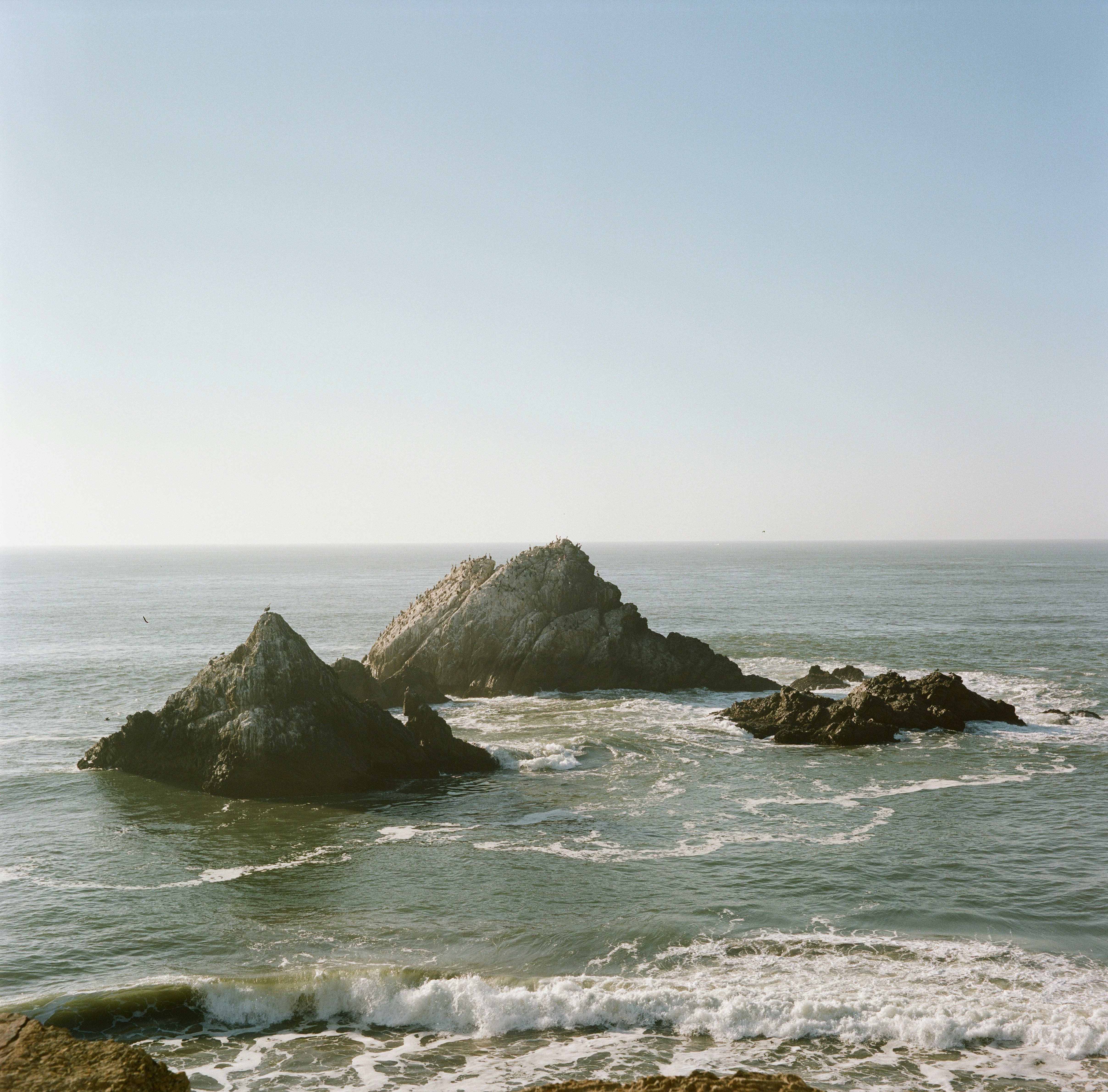 Rocks protrude from the ocean under a clear sky. photo – Free Sea Image ...