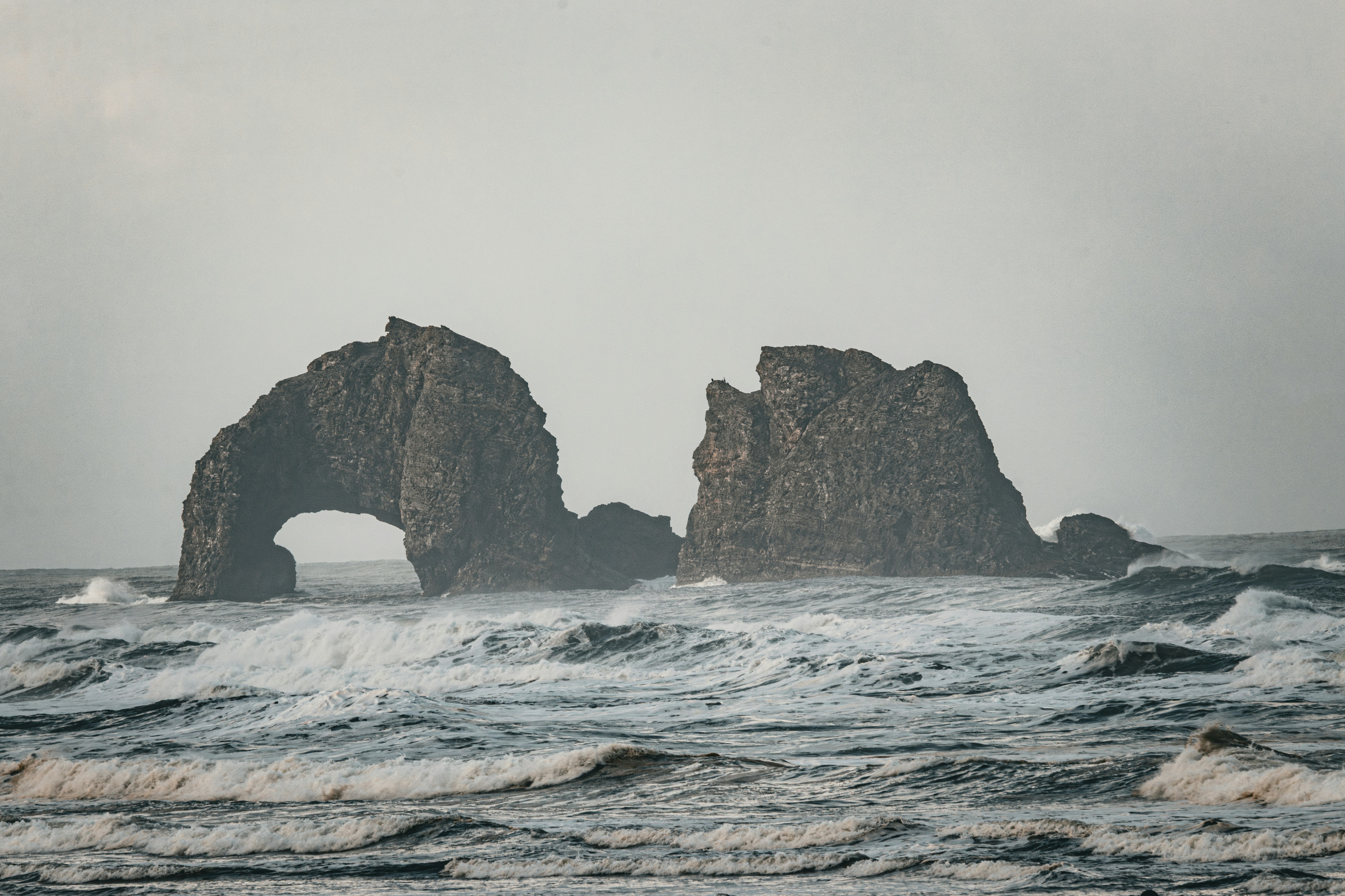 Sea stacks endure turbulent waves in overcast weather. photo – Free ...