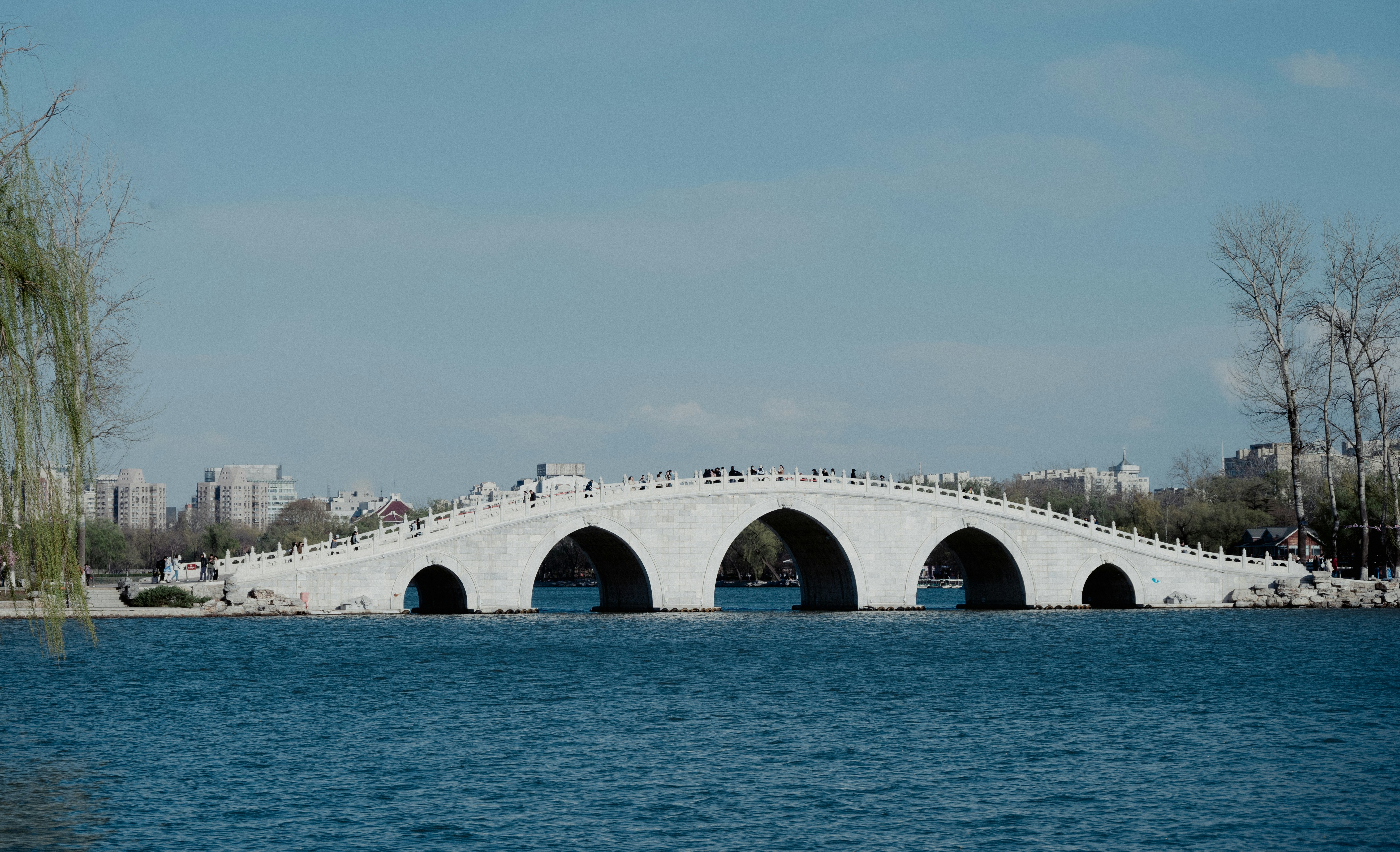A stone bridge arches over water. photo – Free China Image on Unsplash