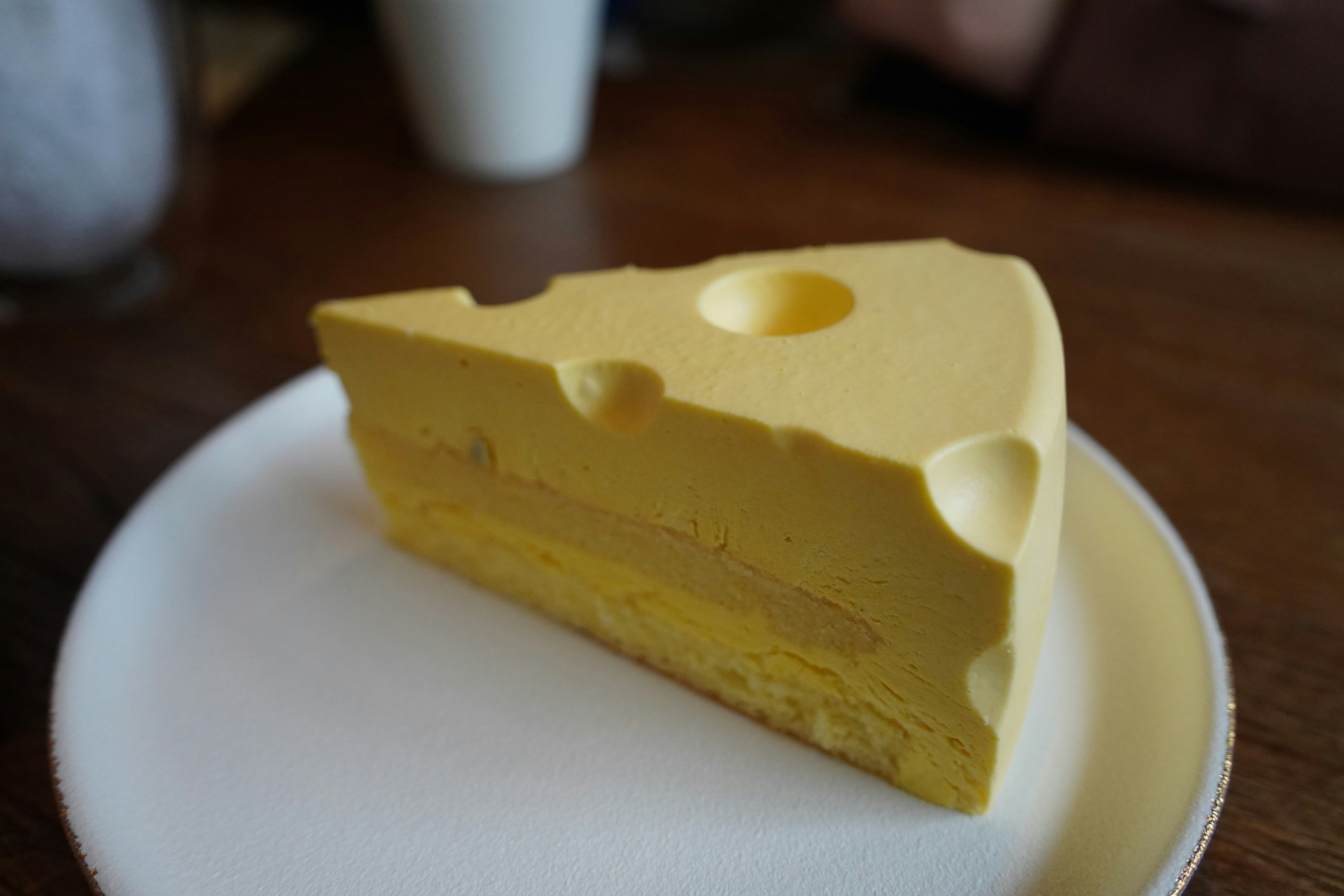 A slice of cheese-shaped cake sits on a plate. photo – Free Image on ...