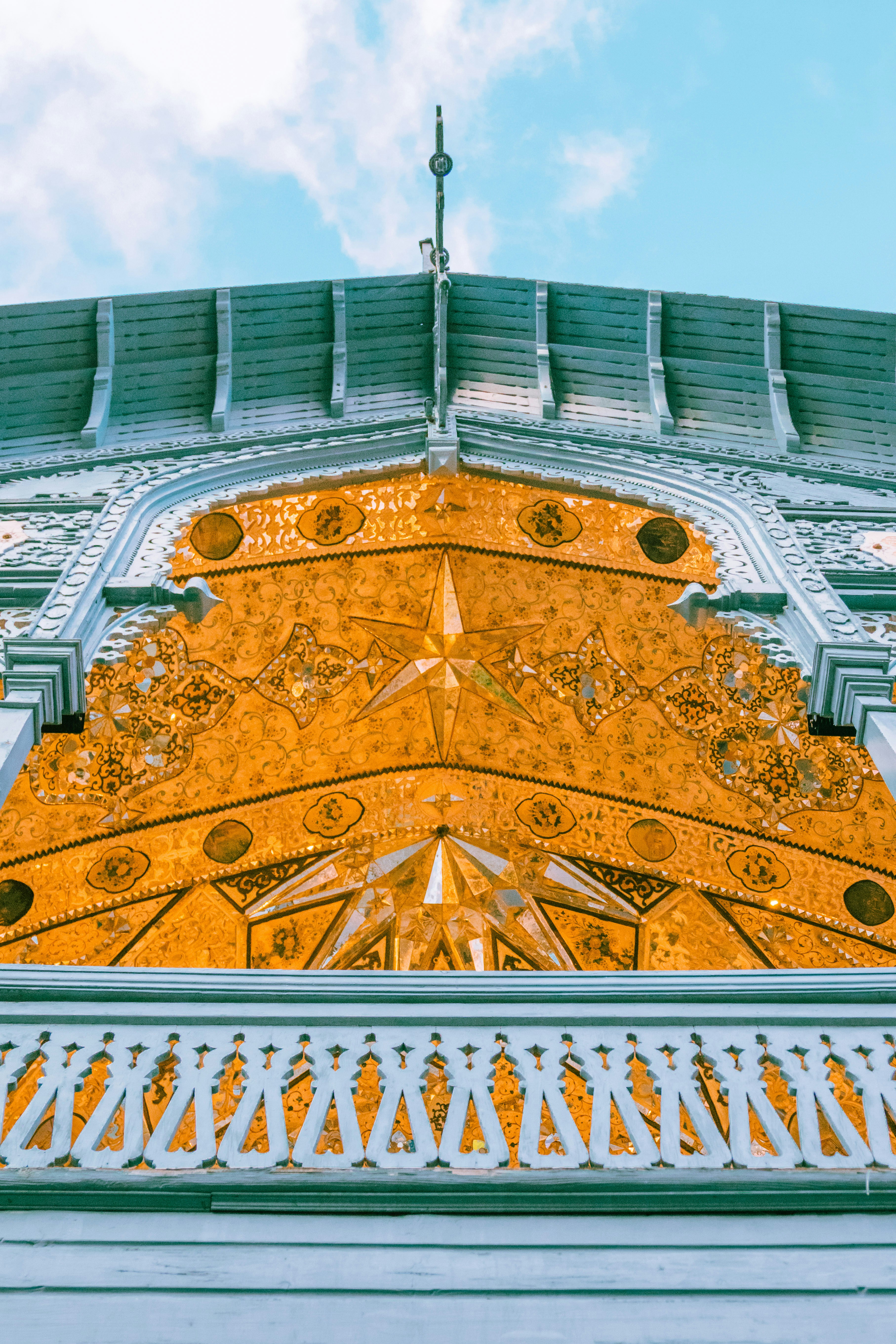 Turquoise balcony with ornate geometric patterns under a clear sky.