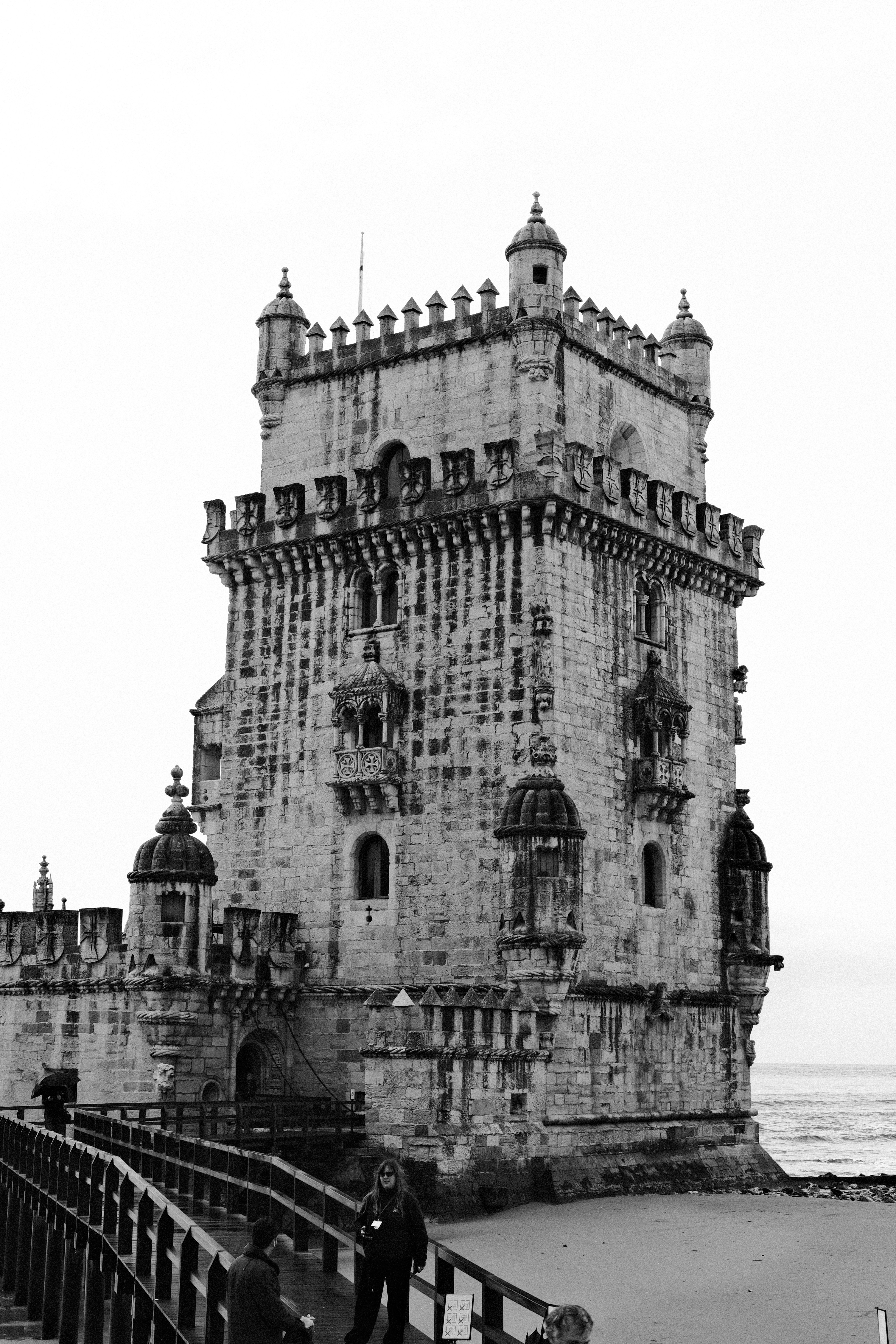 Belem Tower stands majestically against a stark sky, showcasing its historic architecture in black and white.
