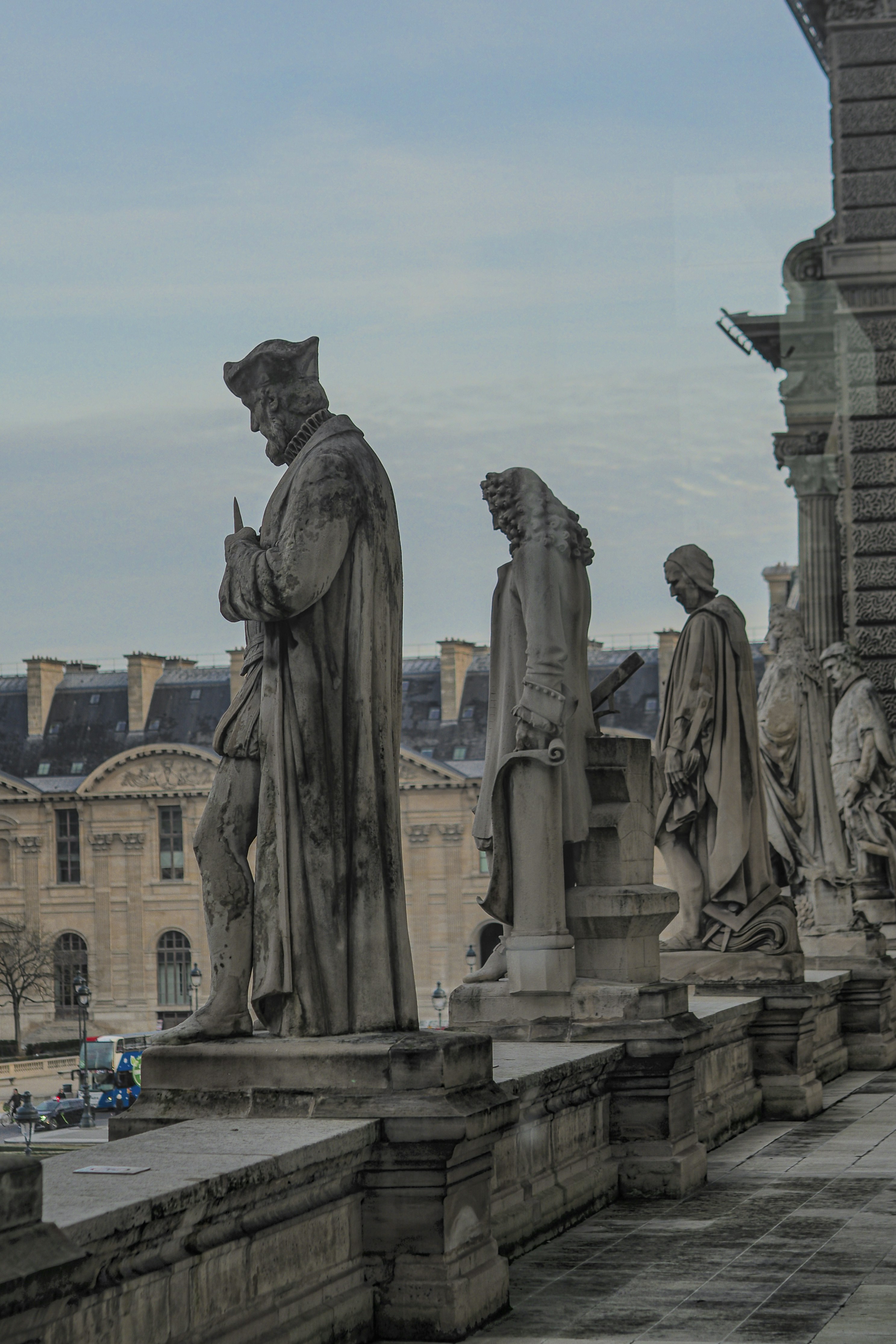 Statues stand on a building overlooking the city. photo – Free Paris ...