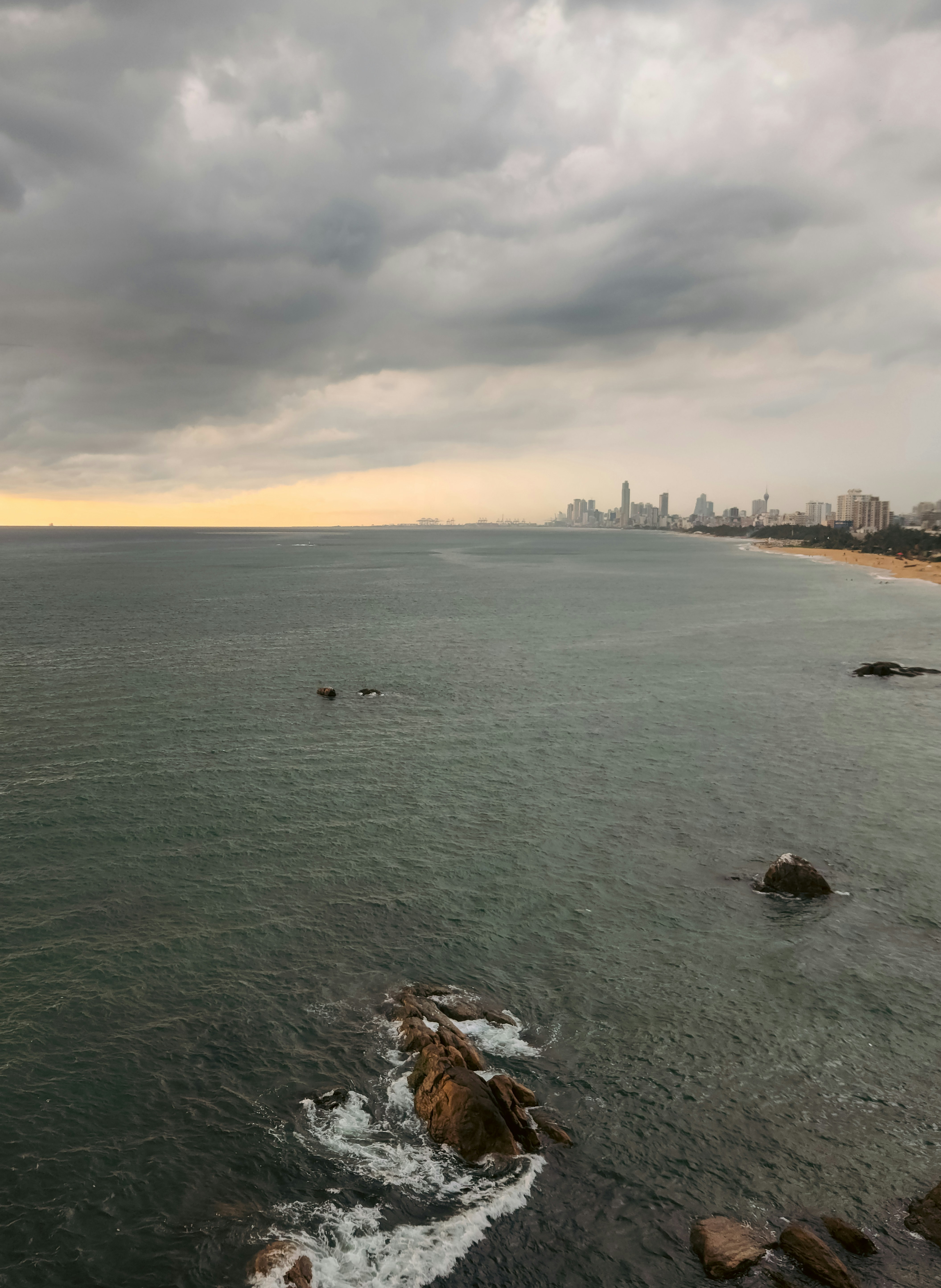Stone Promontory at Dusk: Waves, Sky, and a Distant Skyline