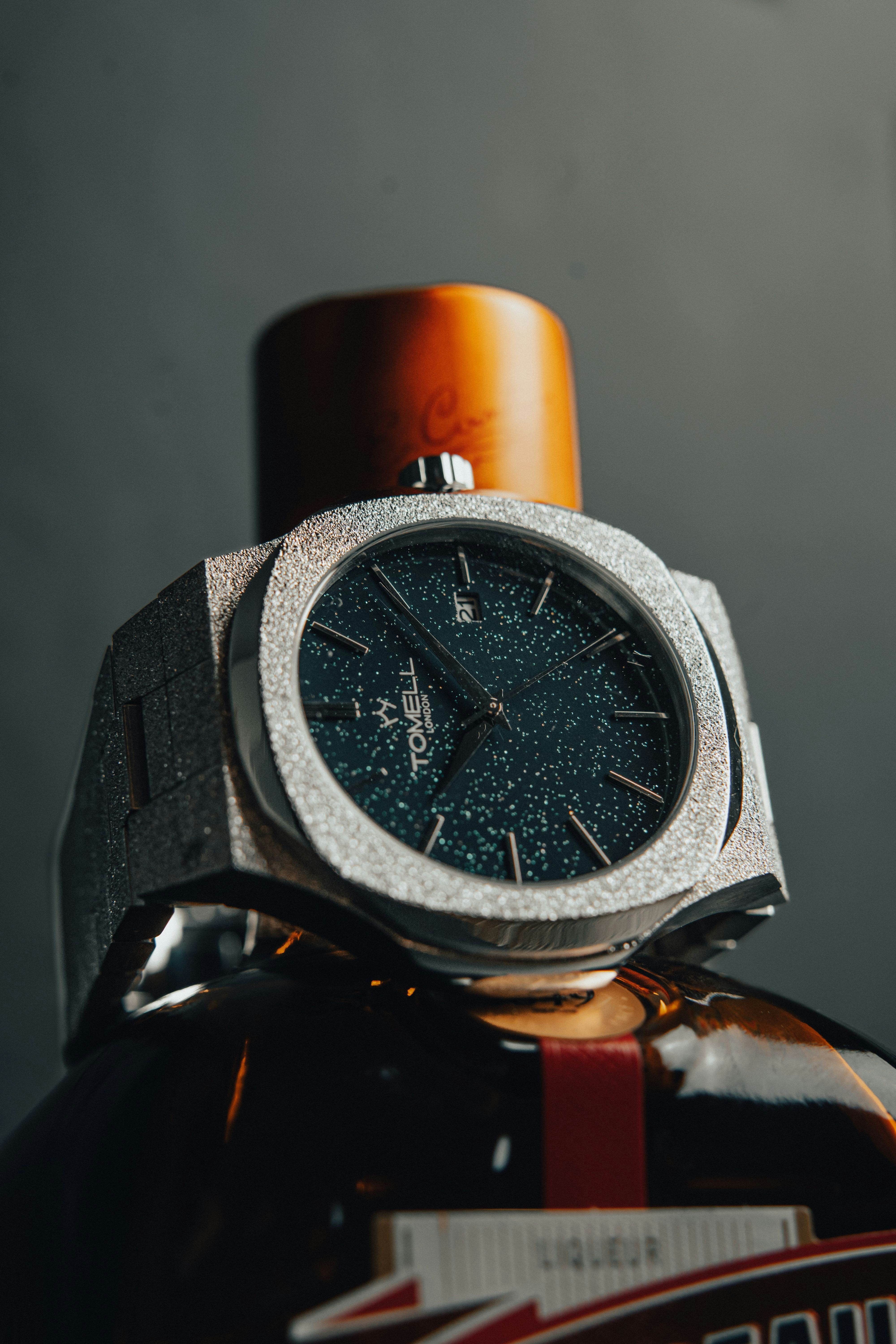 A luxurious watch rests on a bottle. photo – Free Image on Unsplash