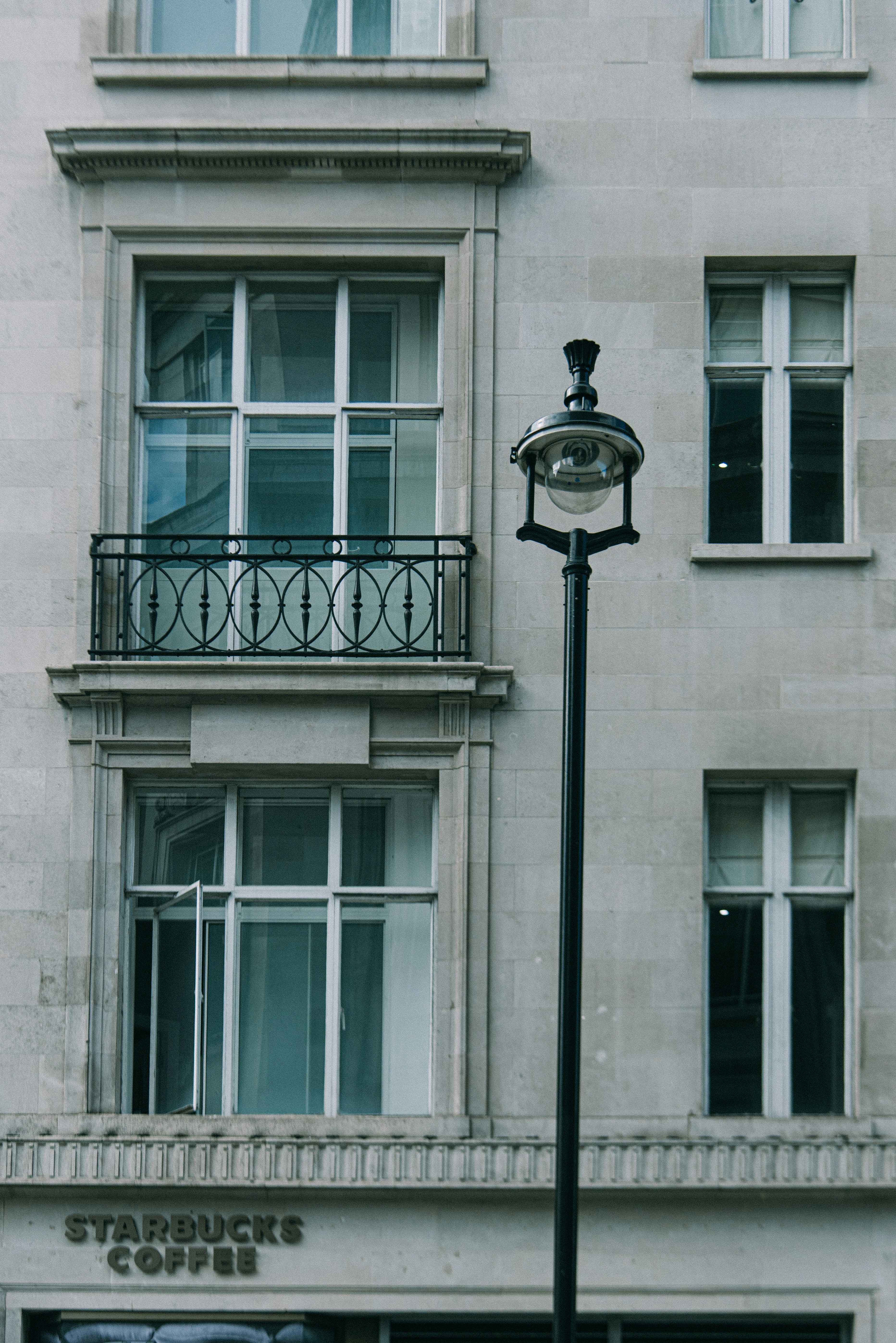 Lone Streetlamp Framed by a Classical Stone Facade and a Starbucks Sign