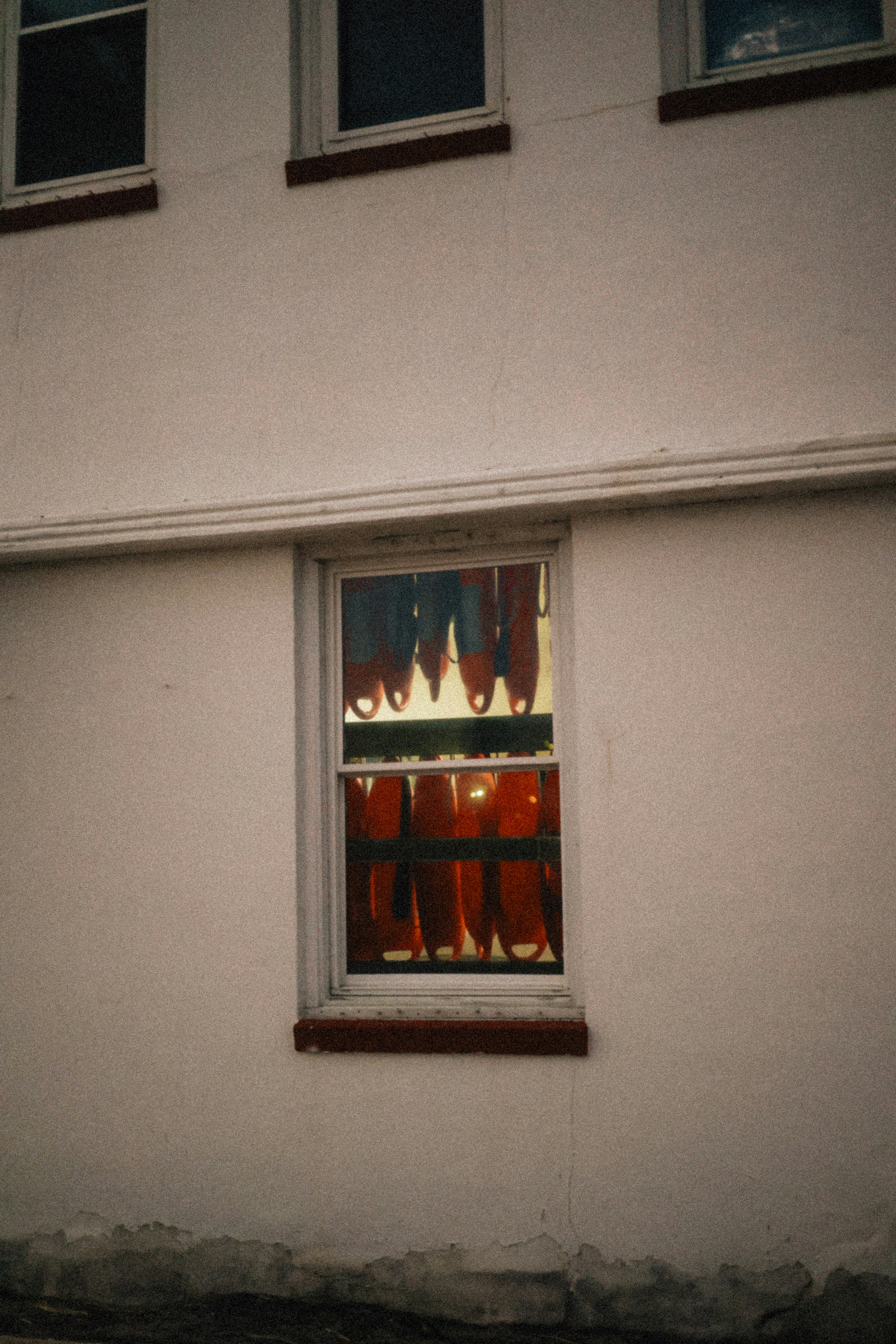 Crimson Hangings Behind a Pale Facade Window