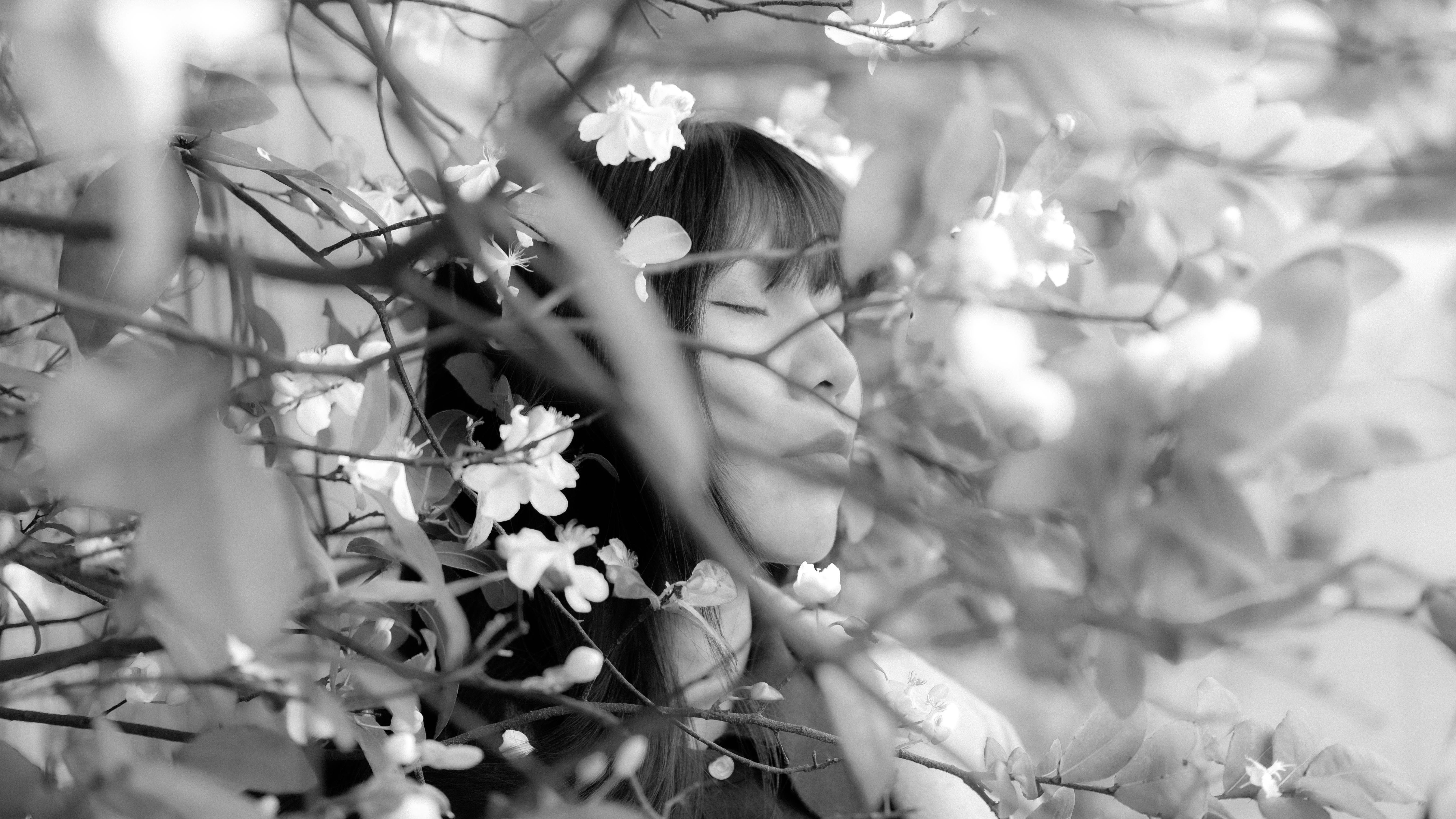 A woman peeks through flowers in black and white. photo – Free Image on Unsplash