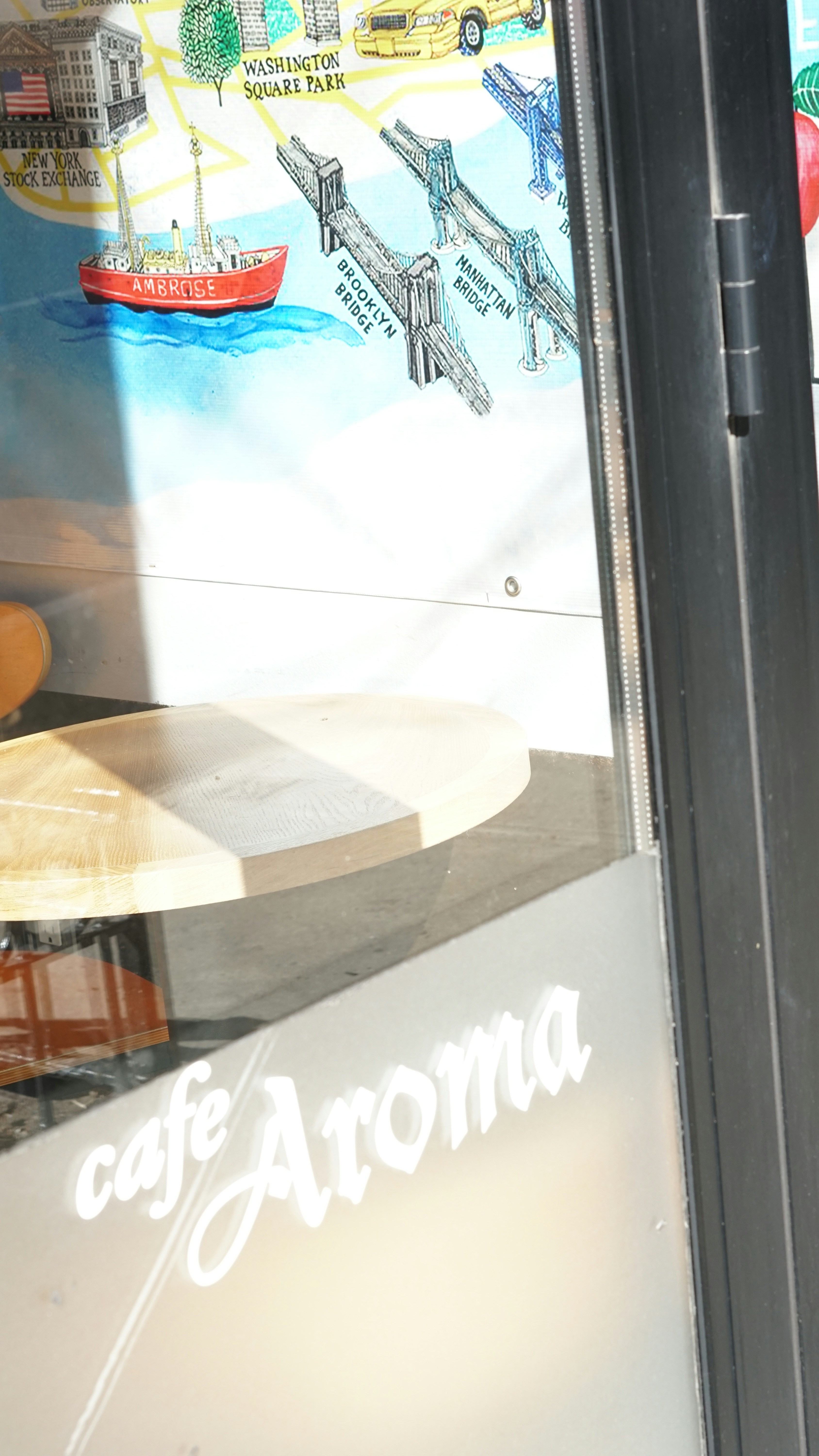 Glass door reflecting a colorful mural with 'Cafe Aroma' written in white script.