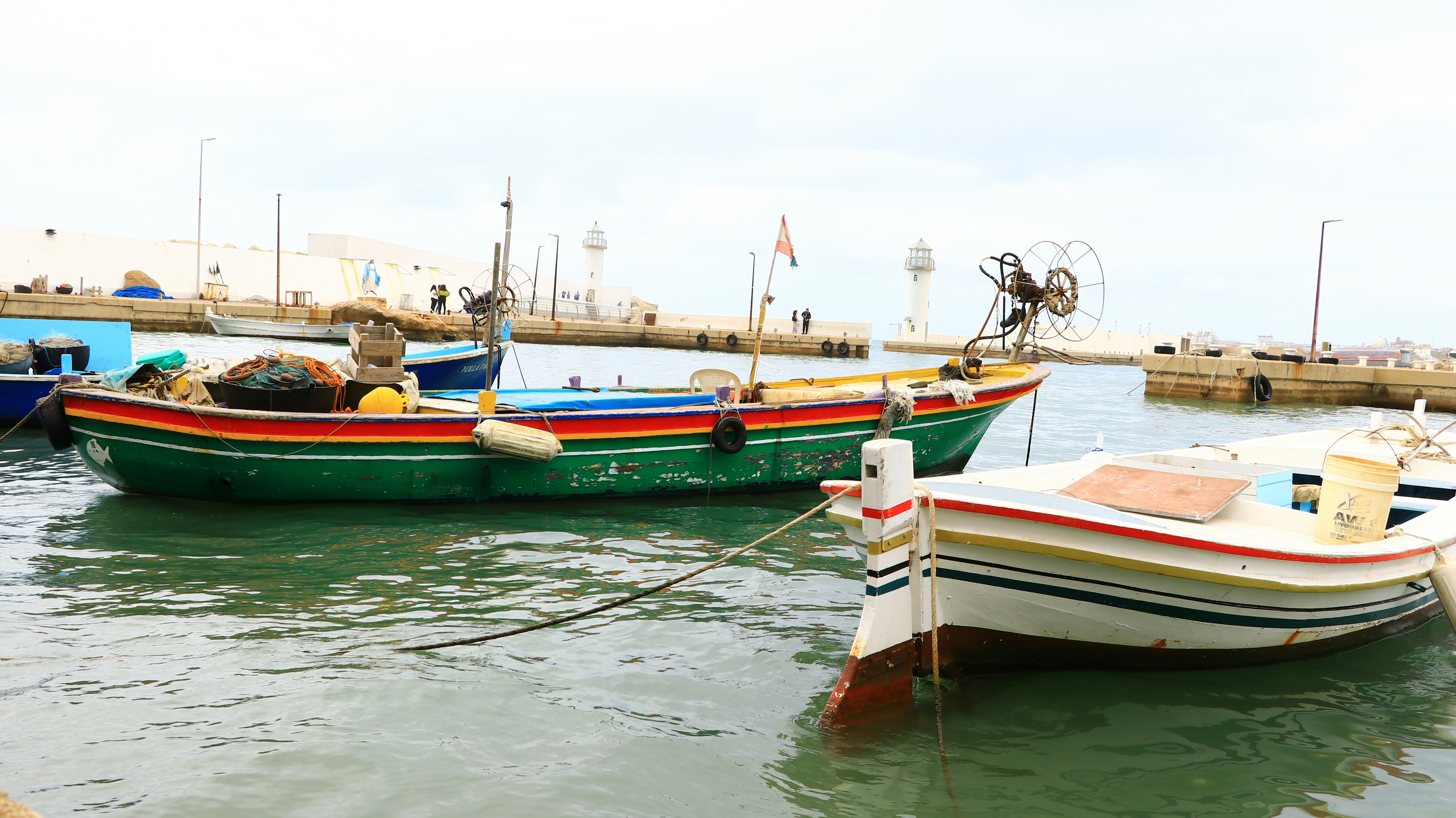 Colorful fishing boats anchored in a calm harbor under an overcast sky.