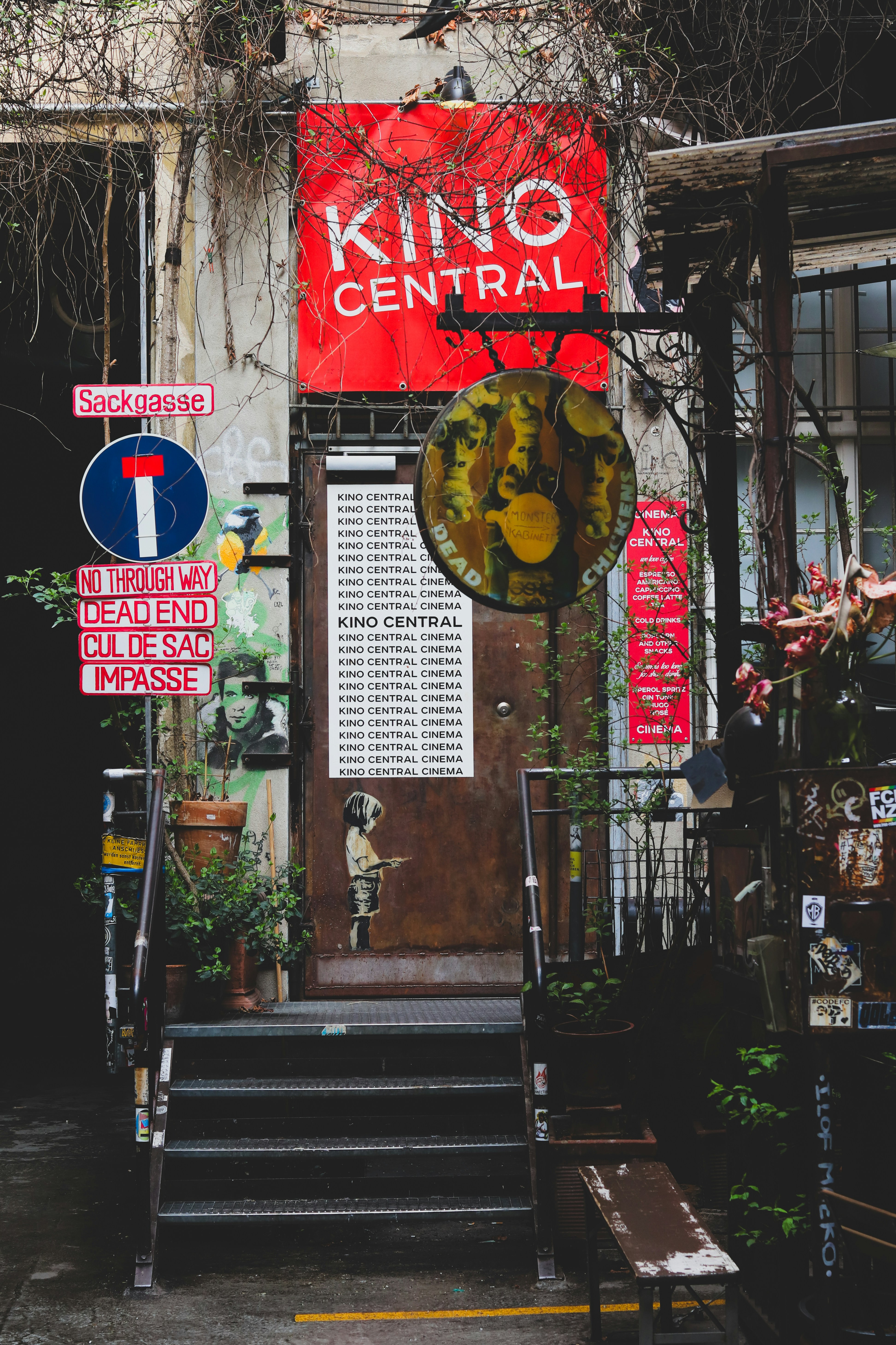 Entrance to a rustic cinema adorned with bright red signs and eclectic decor.