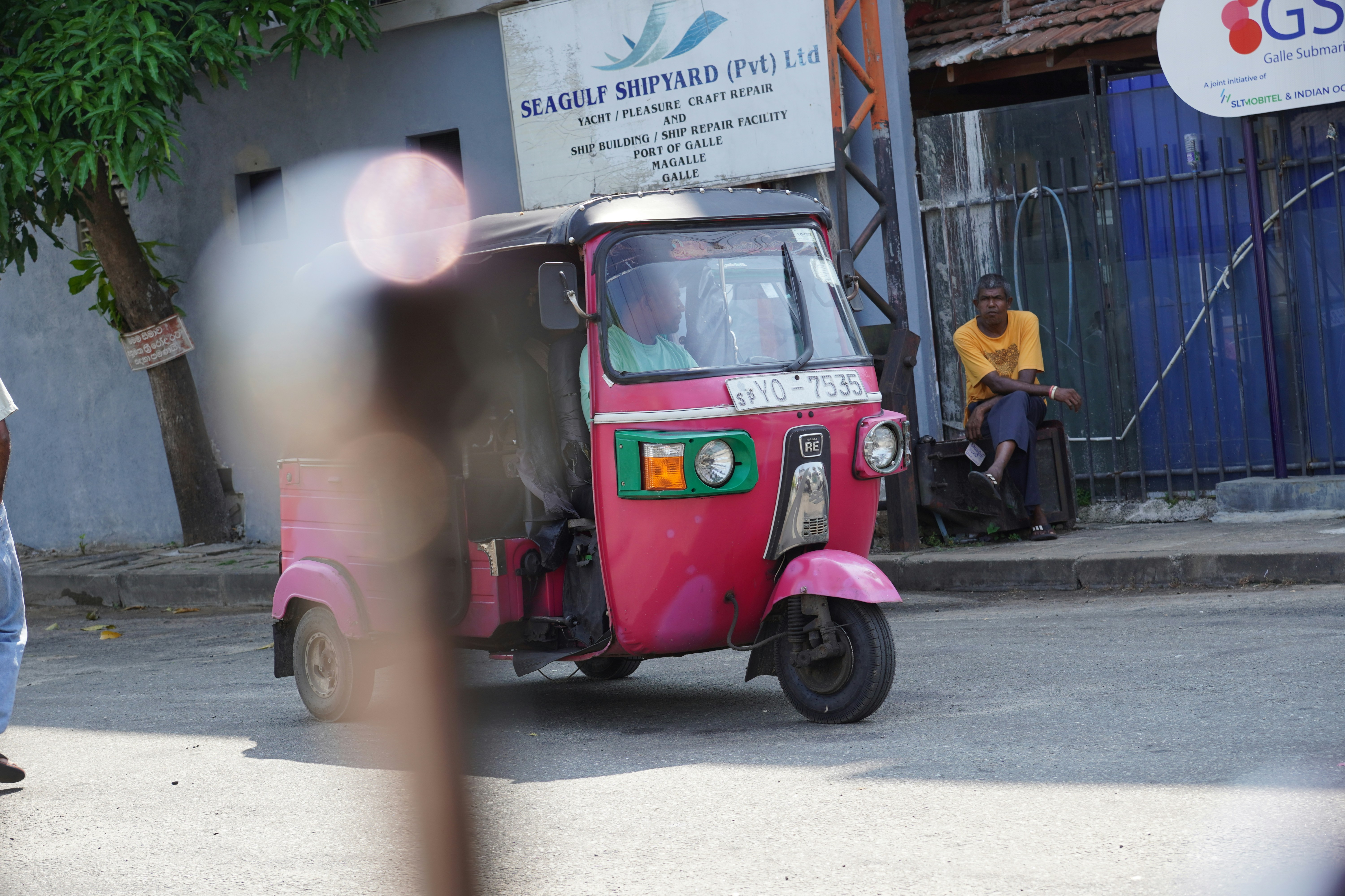 A pink tuk-tuk drives down a street. photo – Free Woman Image on Unsplash
