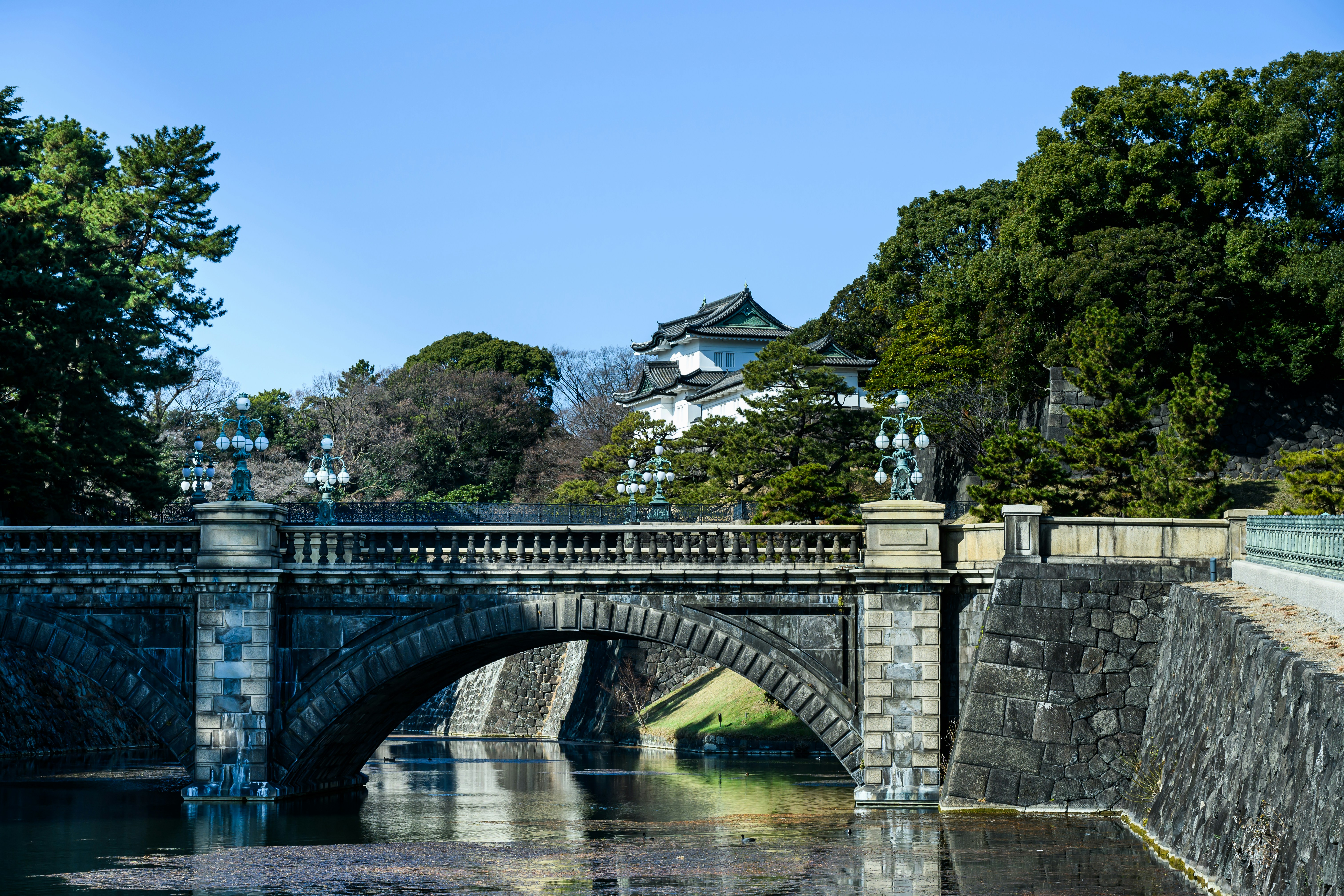 Now the emperor's home, the Imperial Palace occupies the site of the original Edo-jō, the Tokugawa shogunate's castle. Little remains today apart from the moat and stone walls. | Stone bridge leads to a traditional japanese building.