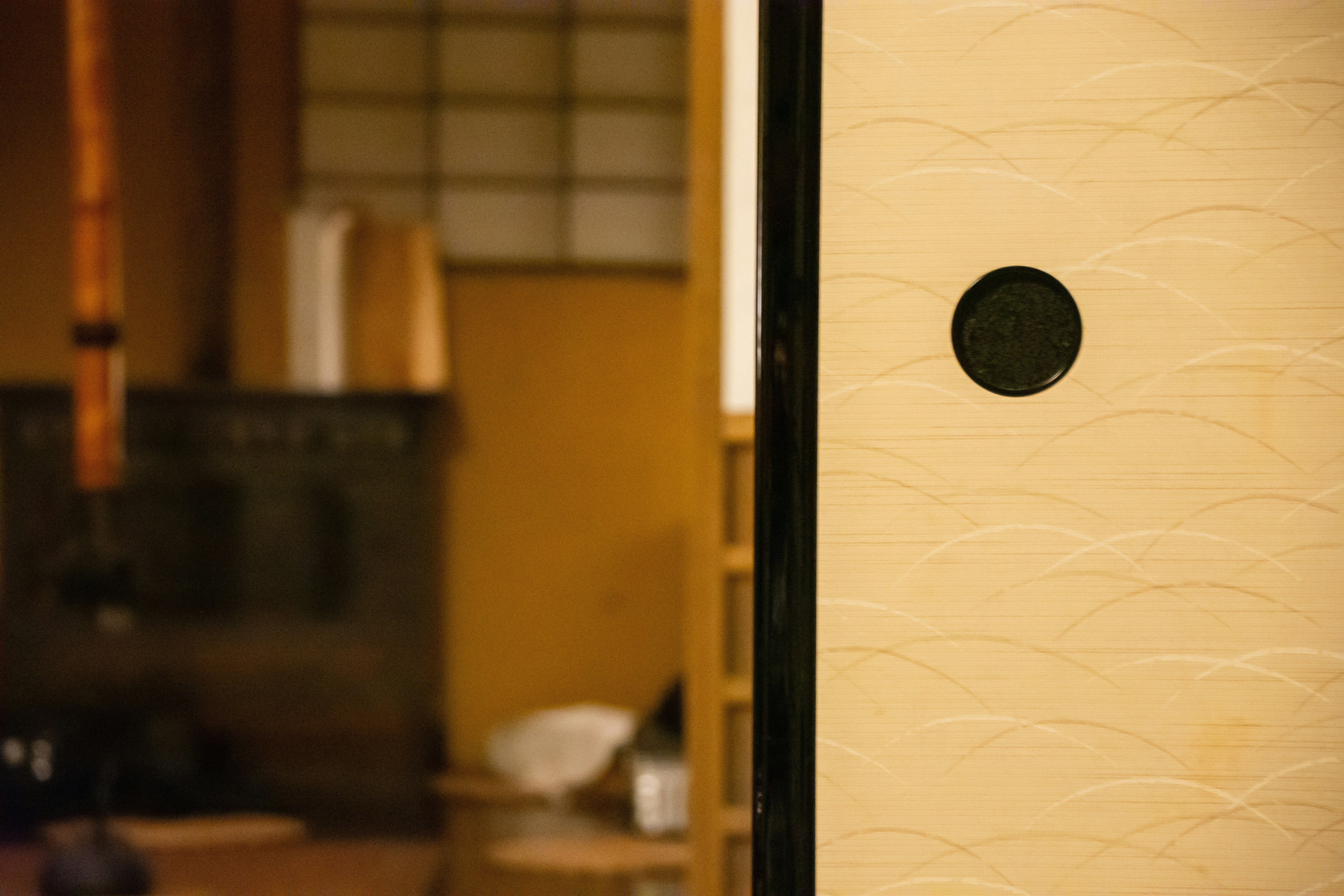 Traditional Japanese interior with a focus on a partially open sliding door revealing a dimly lit room.