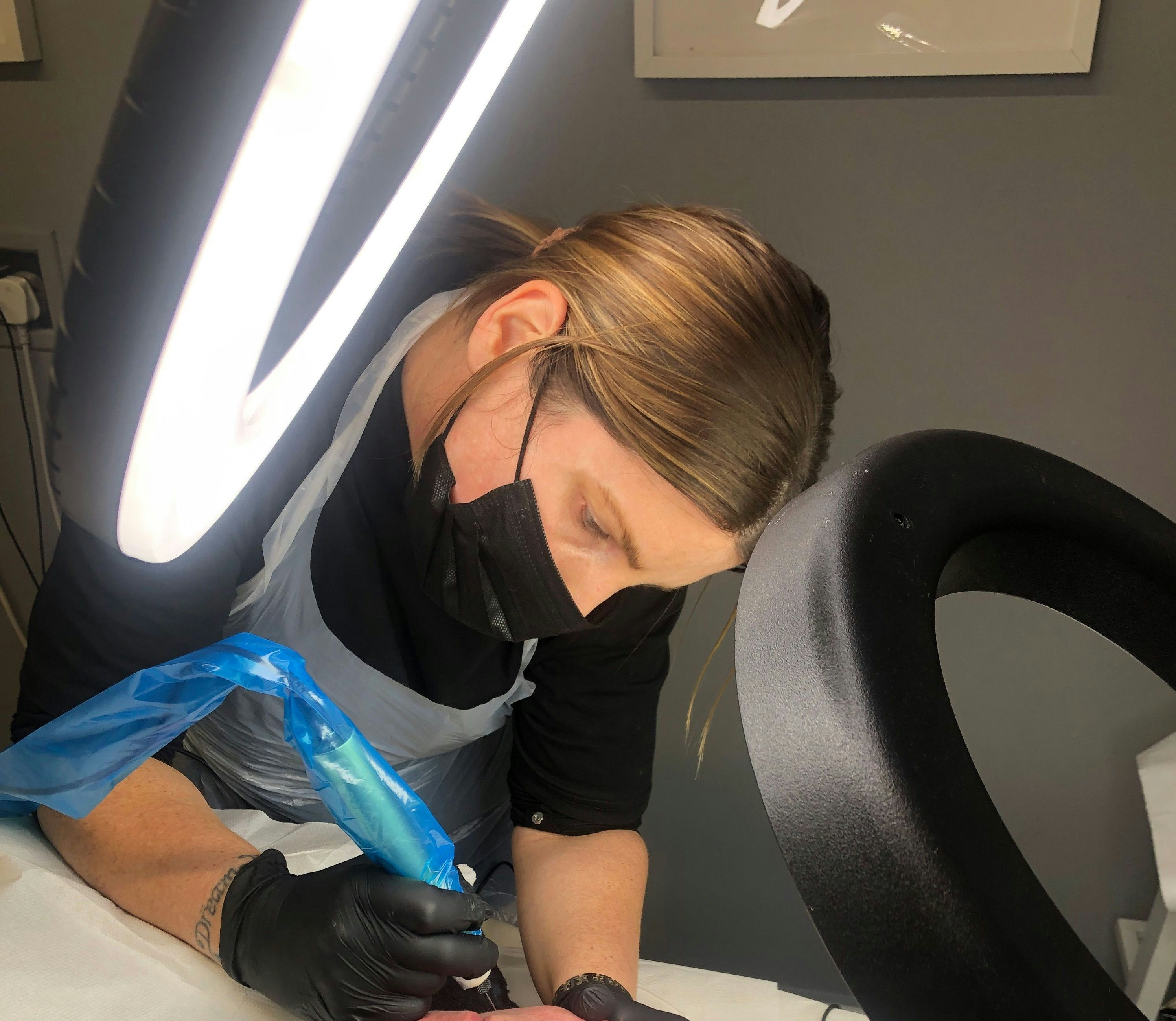 Tattoo artist working on a client with specialized lighting. photo ...