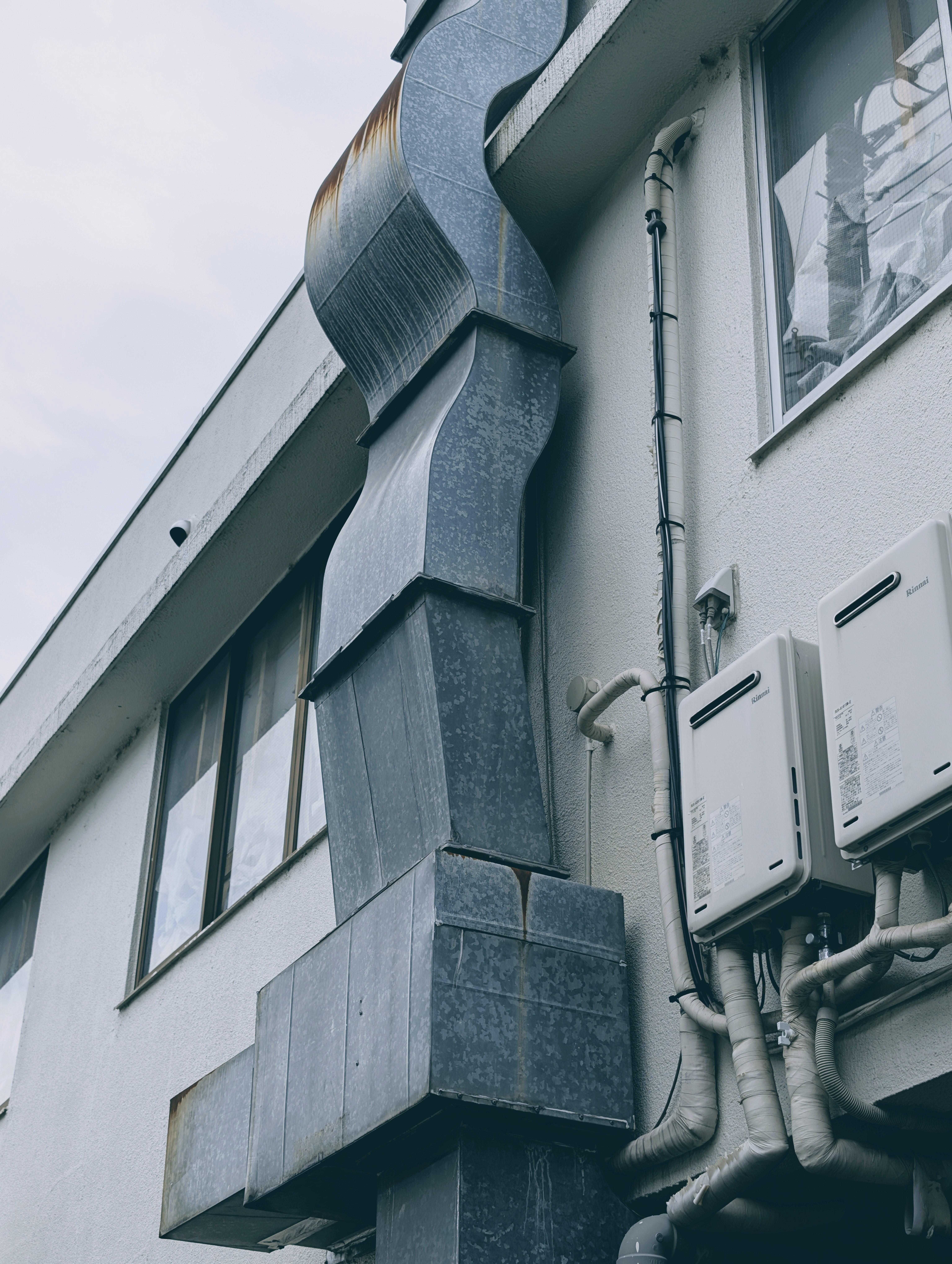 An industrial exhaust duct clings to the building.