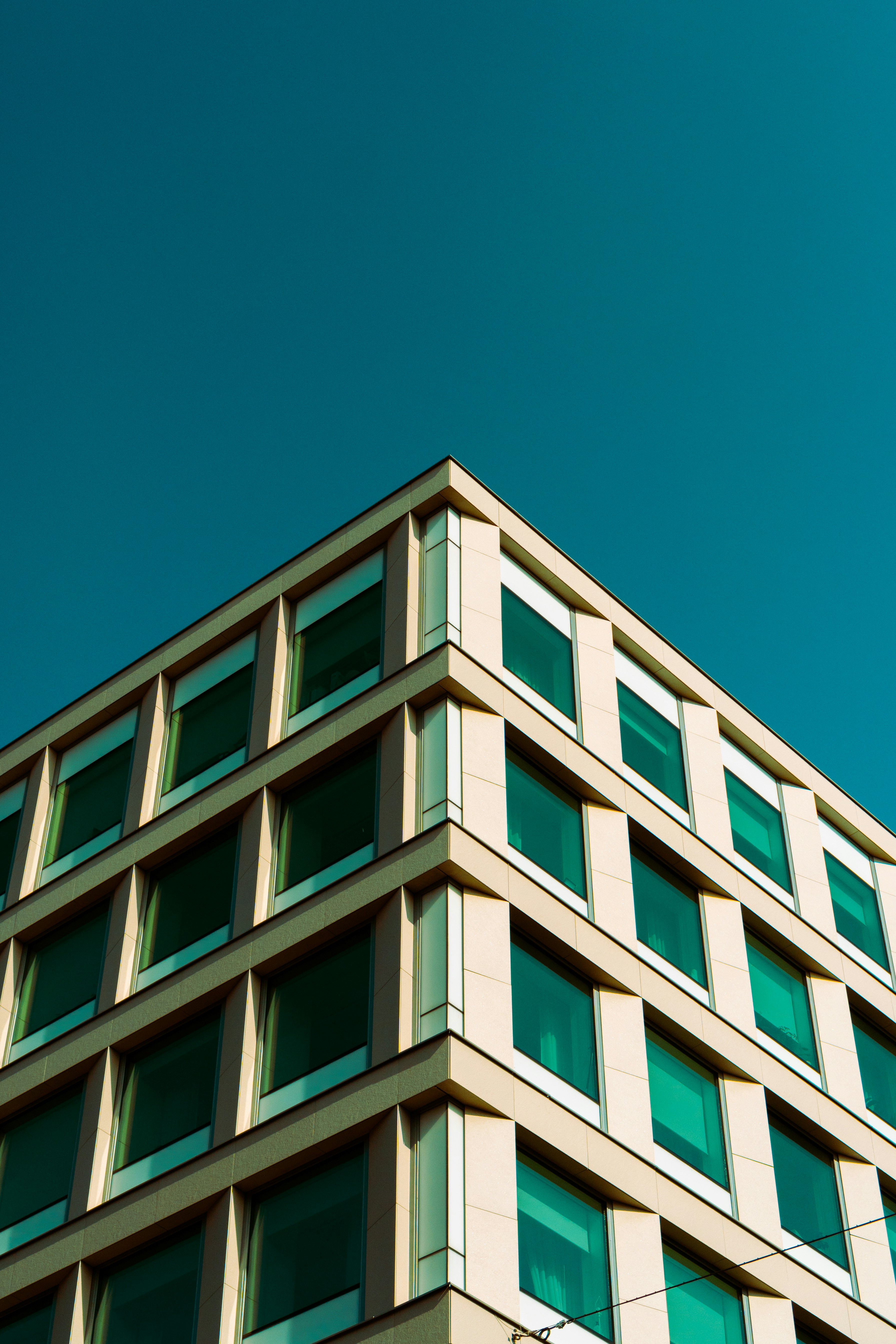 Modern building facade with grid-like windows set against a clear blue sky.