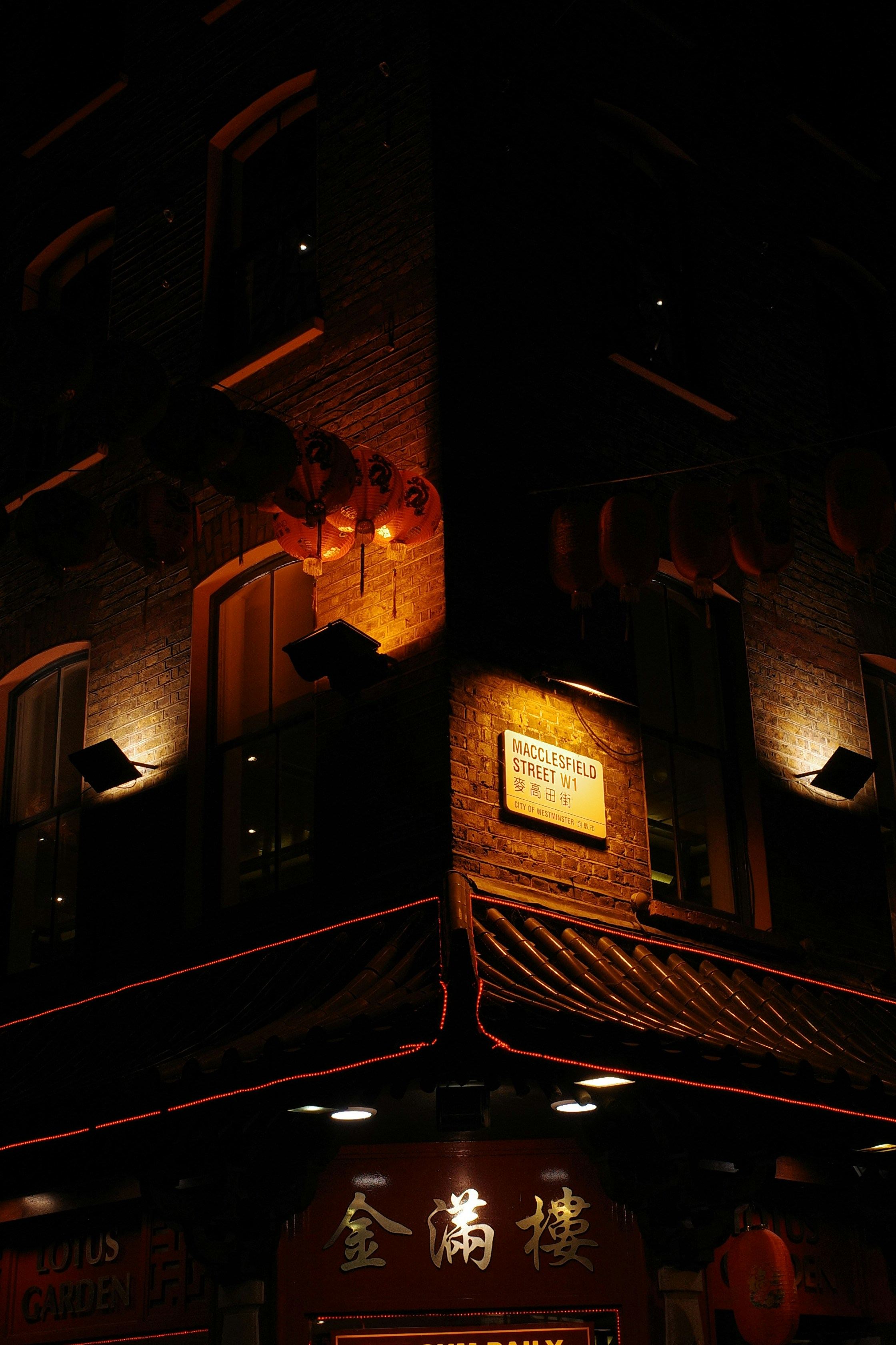 Dimly lit street corner with warm lights illuminating a brick building at night.