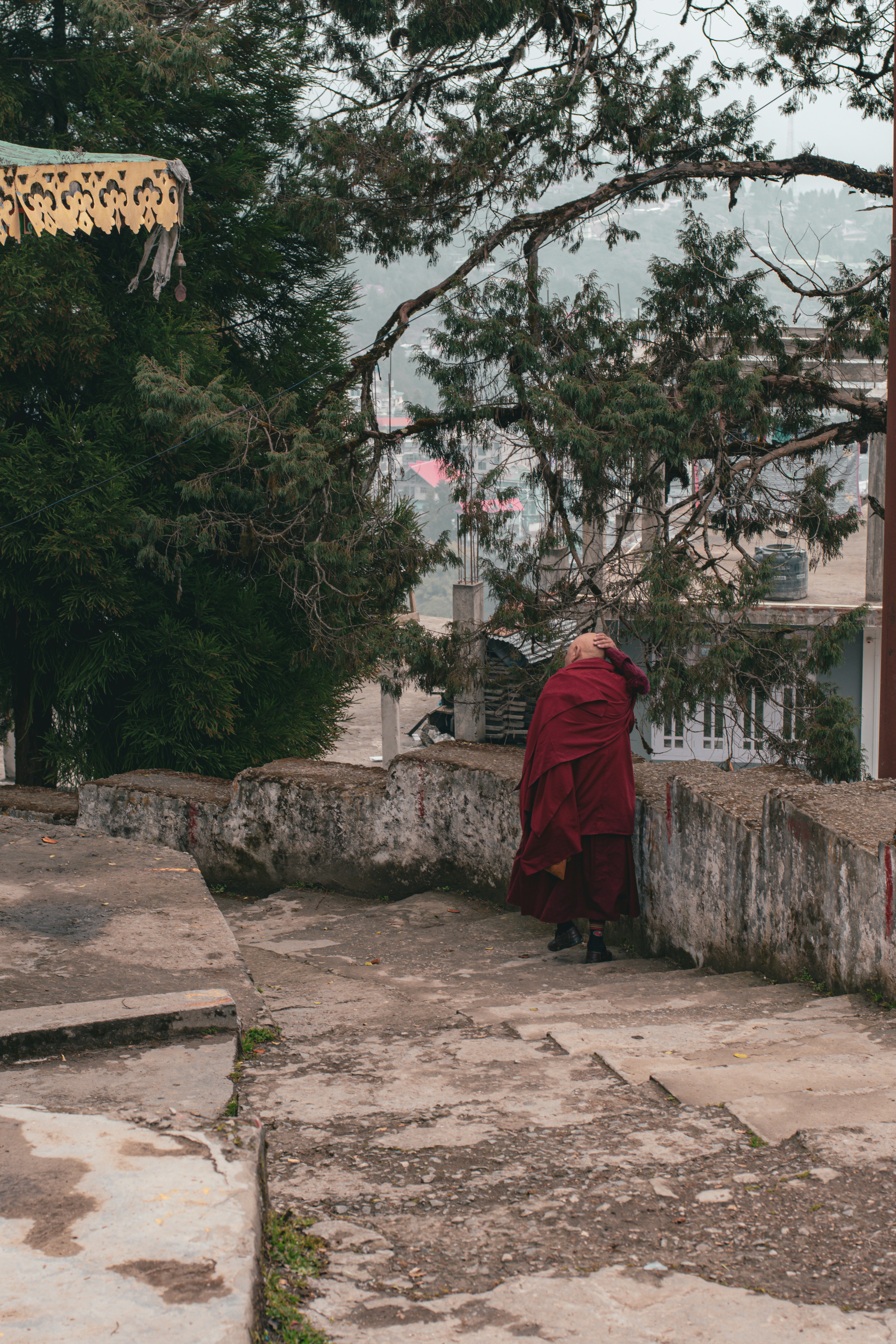 Red-Robed Monk on a Weathered Terrace Overlooking the Village Below