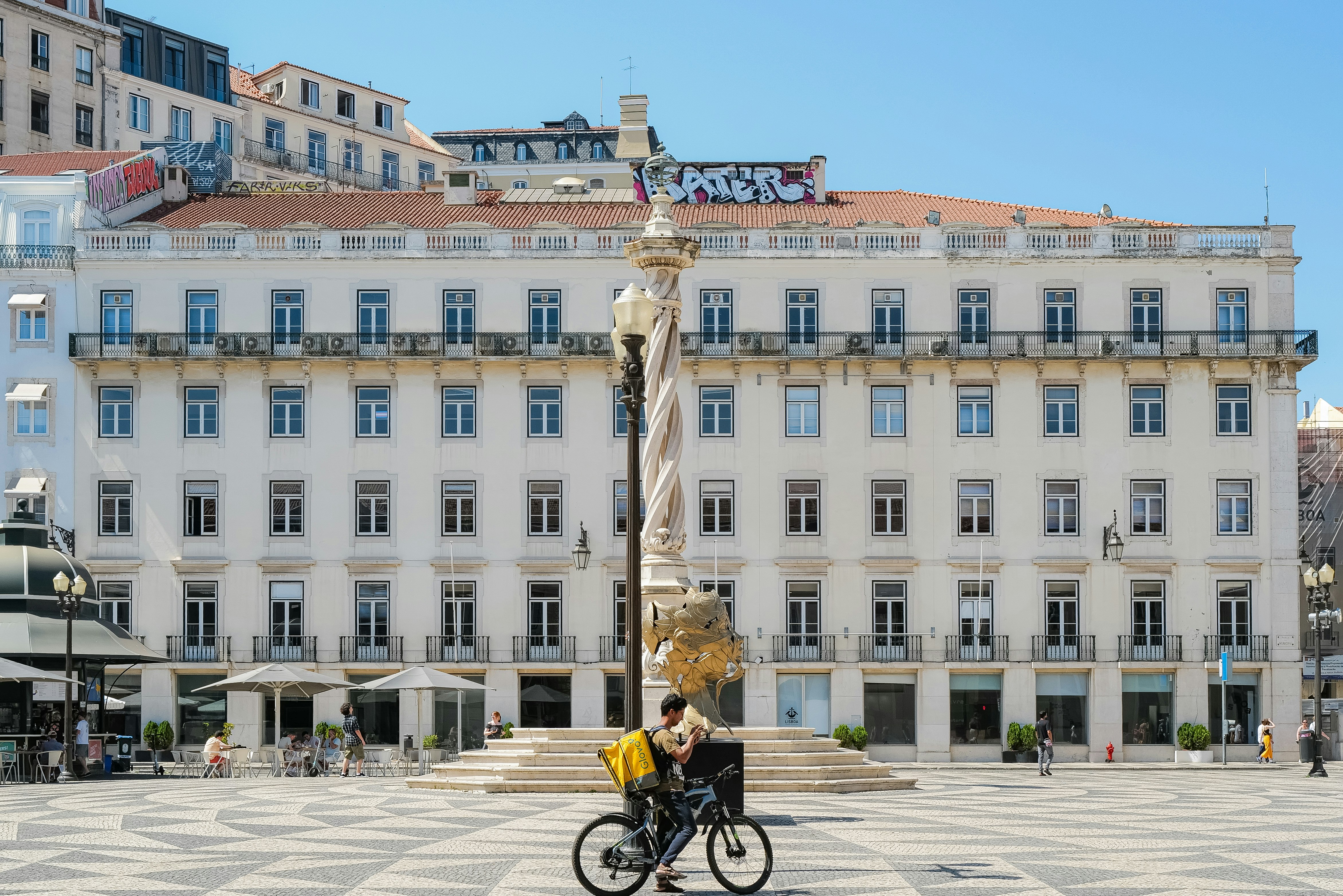 Cyclist in a Sunlit European Plaza Beneath a Regal Fountain