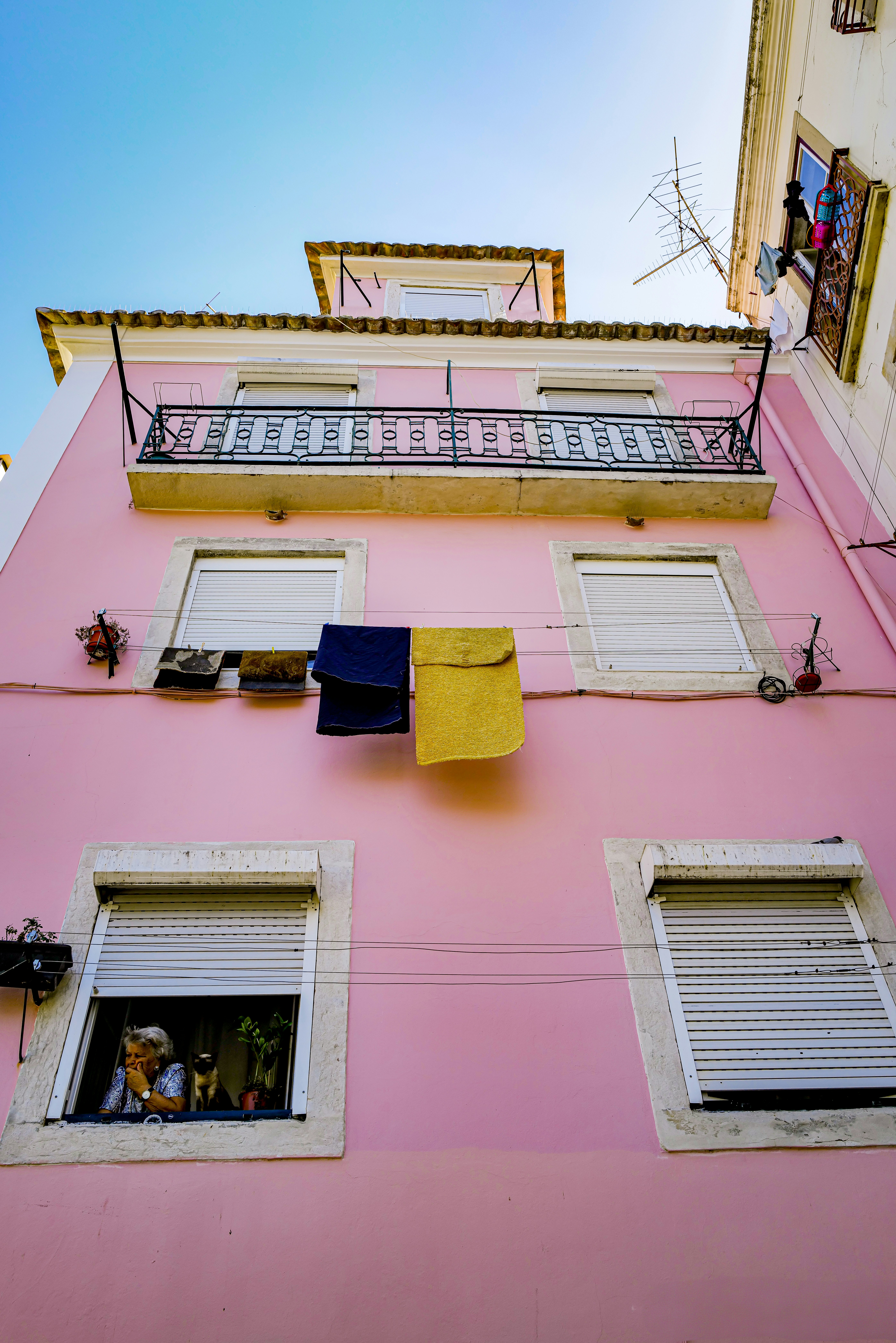 Laundry in Pink: A Sunlit Balcony Scene on a Quiet European Street