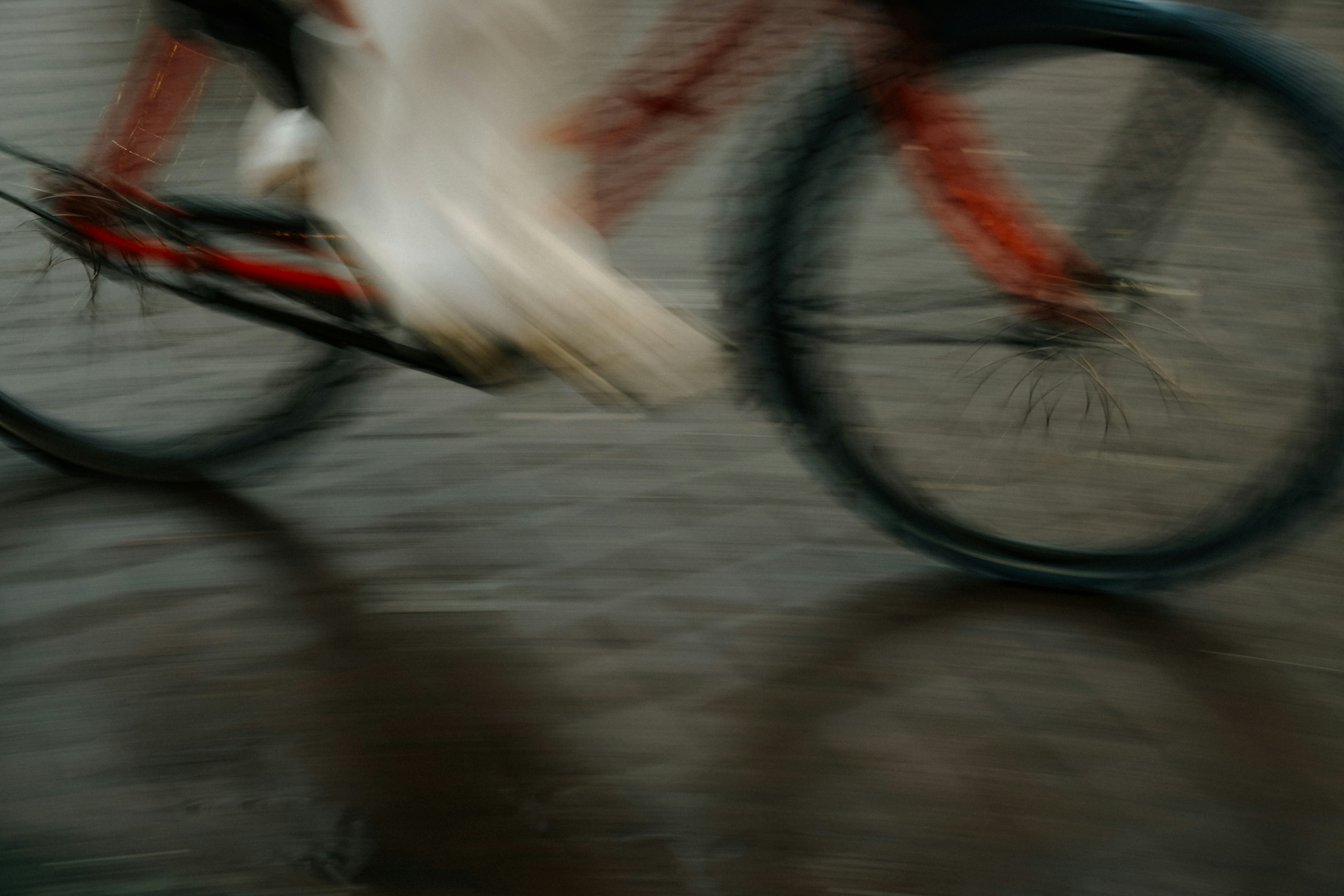 Blurred motion of a cyclist on a wet cobblestone street, emphasizing movement and velocity.
