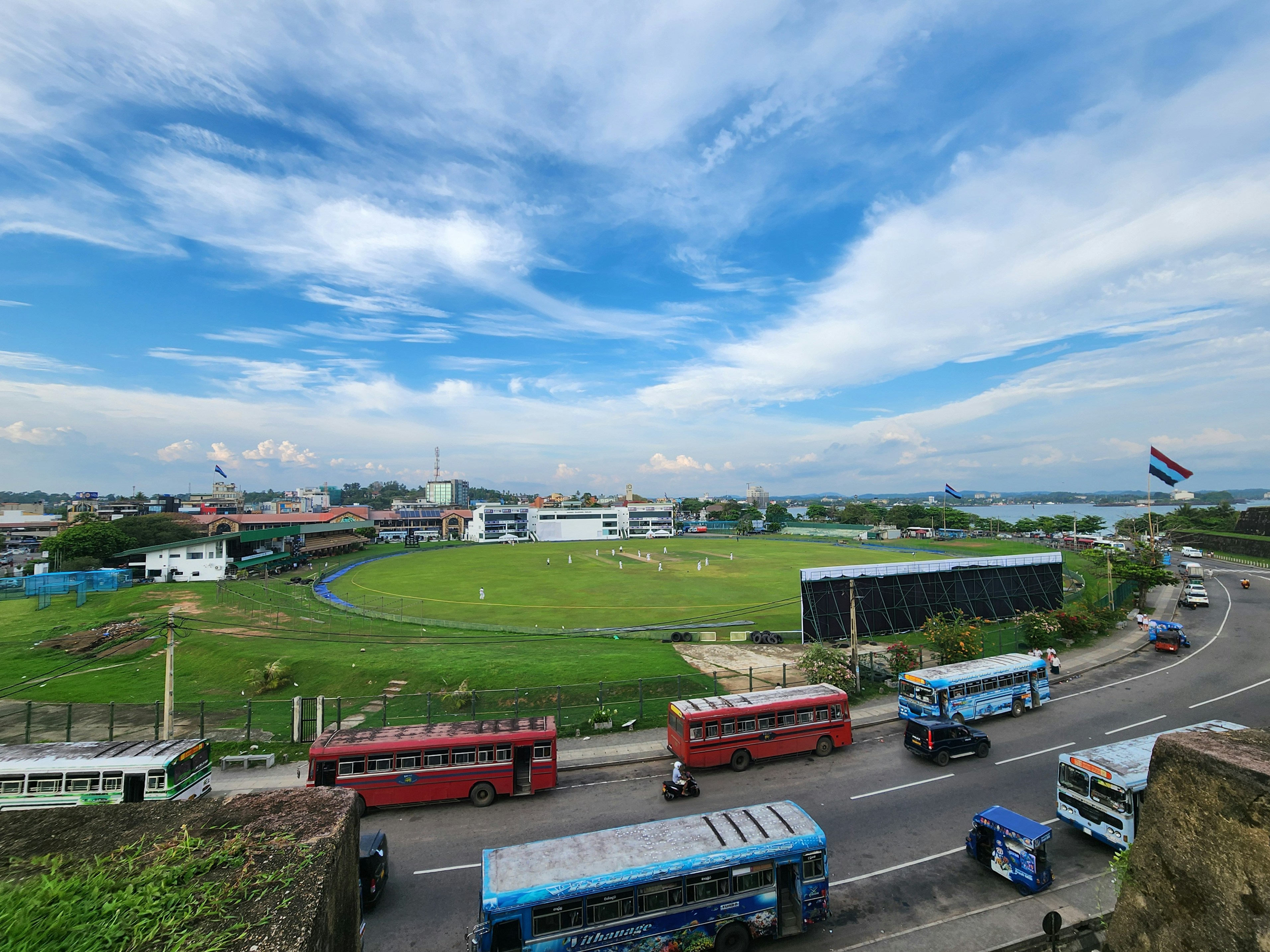 A road with buses is in front of a sports field. photo – Free Wallpaper ...