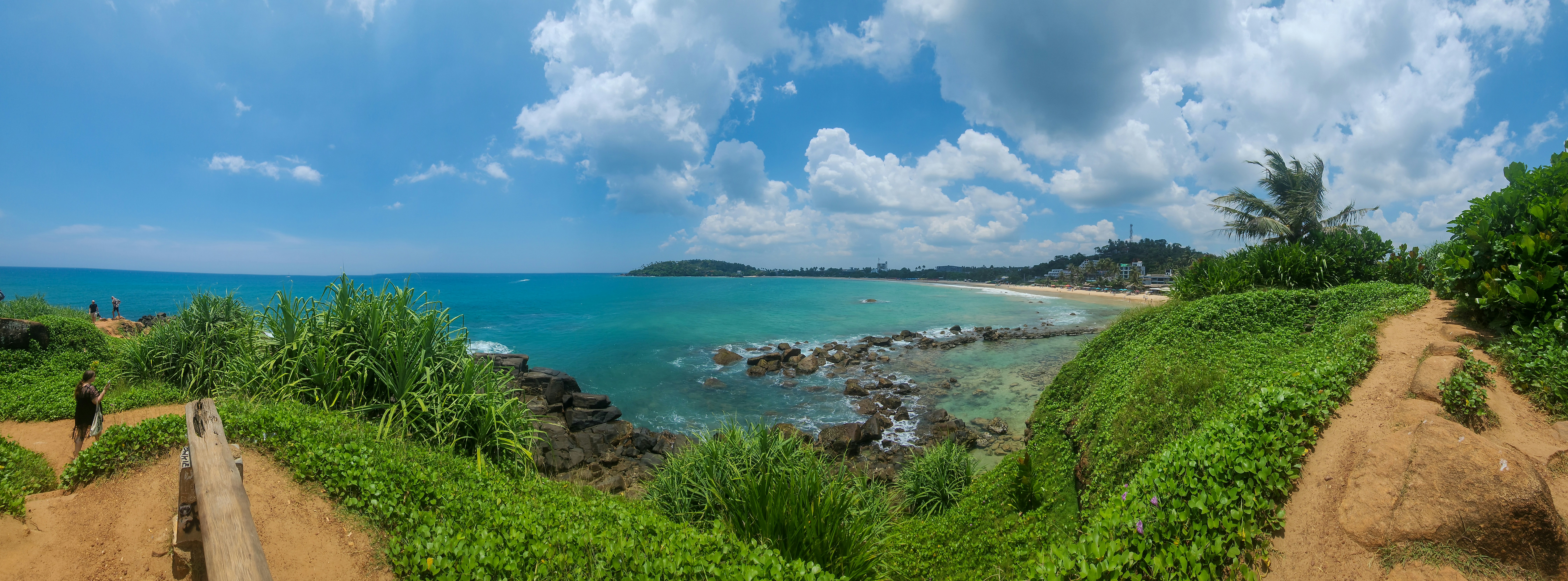 Verdant Cliff Path Reaching a Turquoise Cove Under a Brushed-Blue Sky