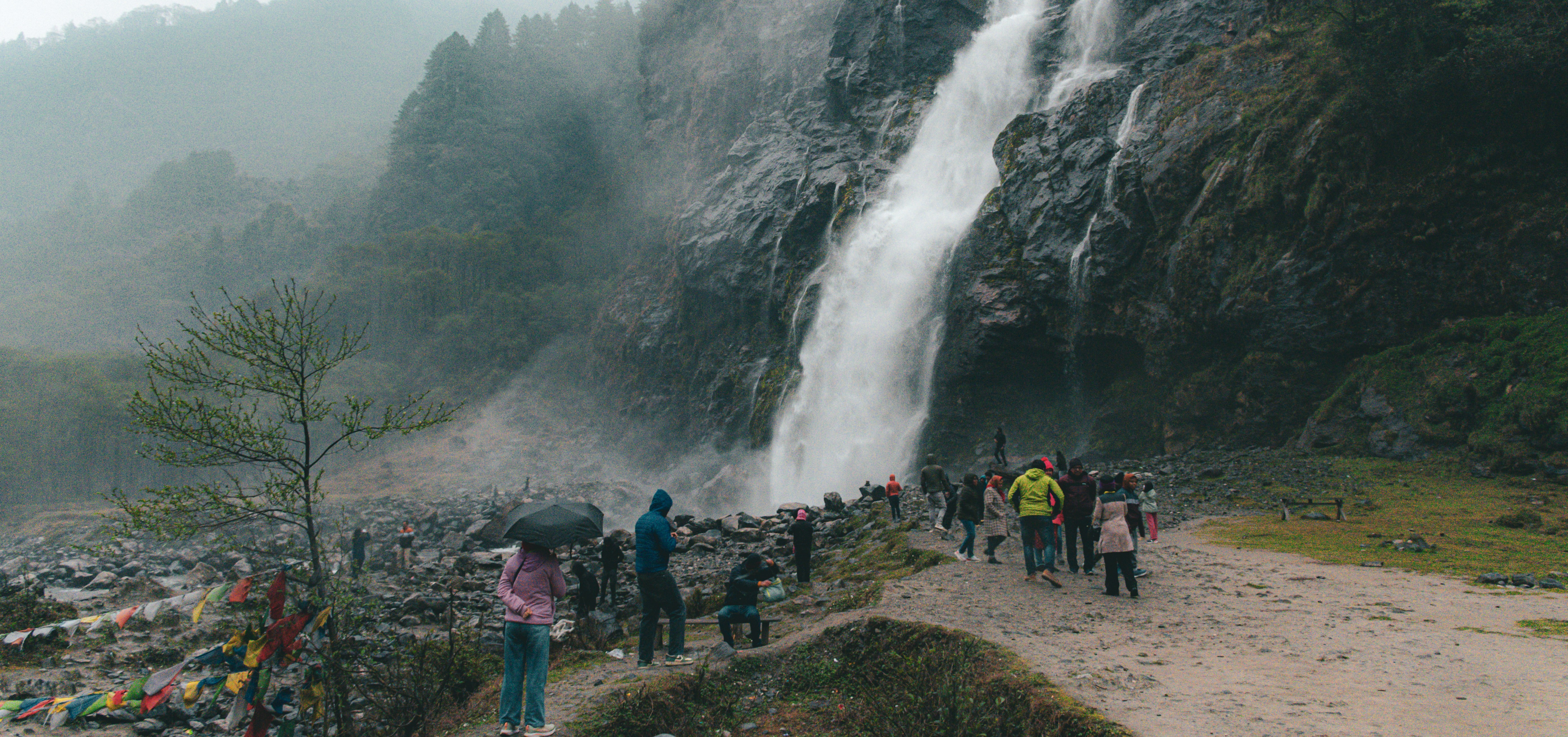 Trail of Mist: Hikers Beside a Veiled Cascade