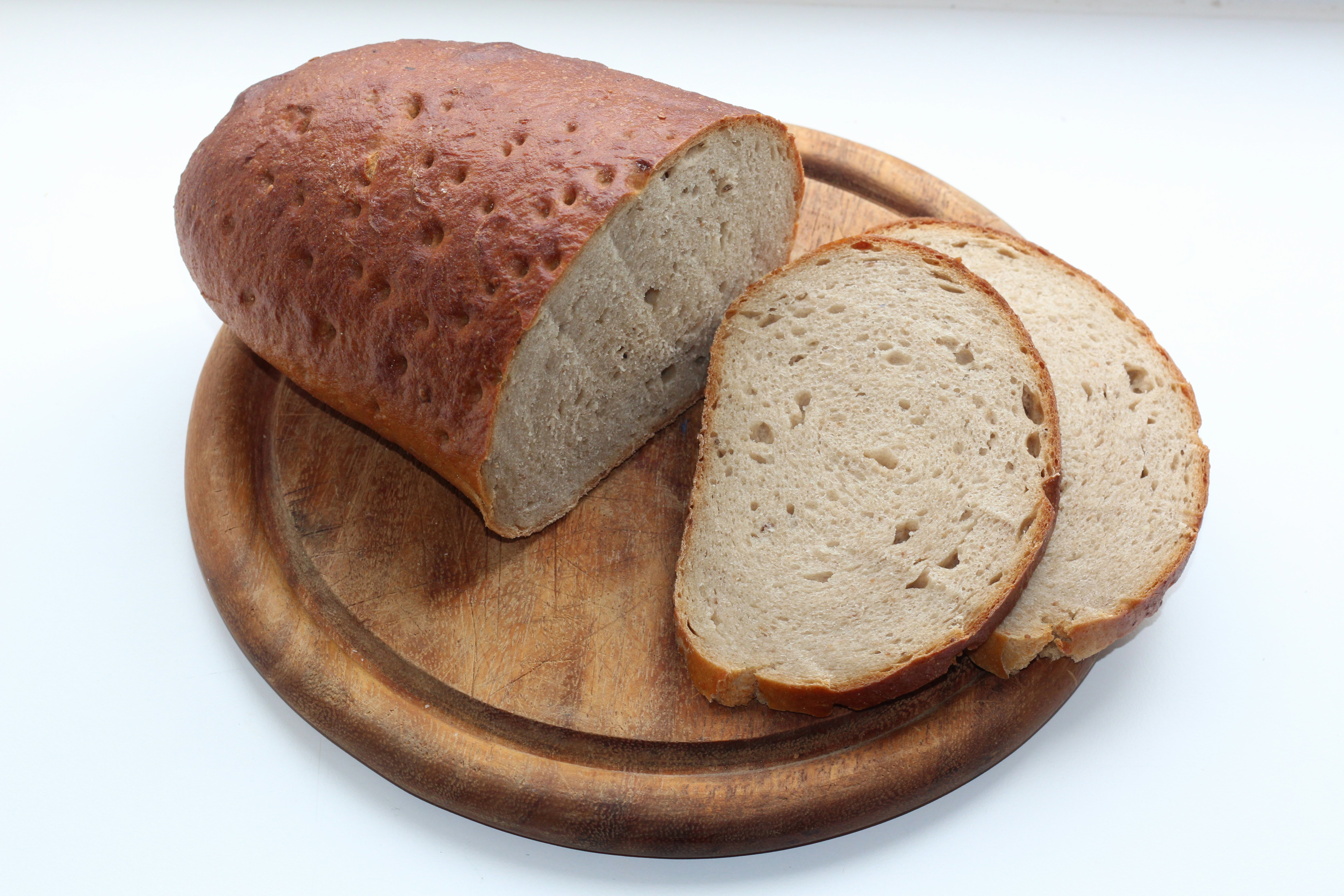 Freshly baked artisan bread loaf with two slices resting on a wooden cutting board.