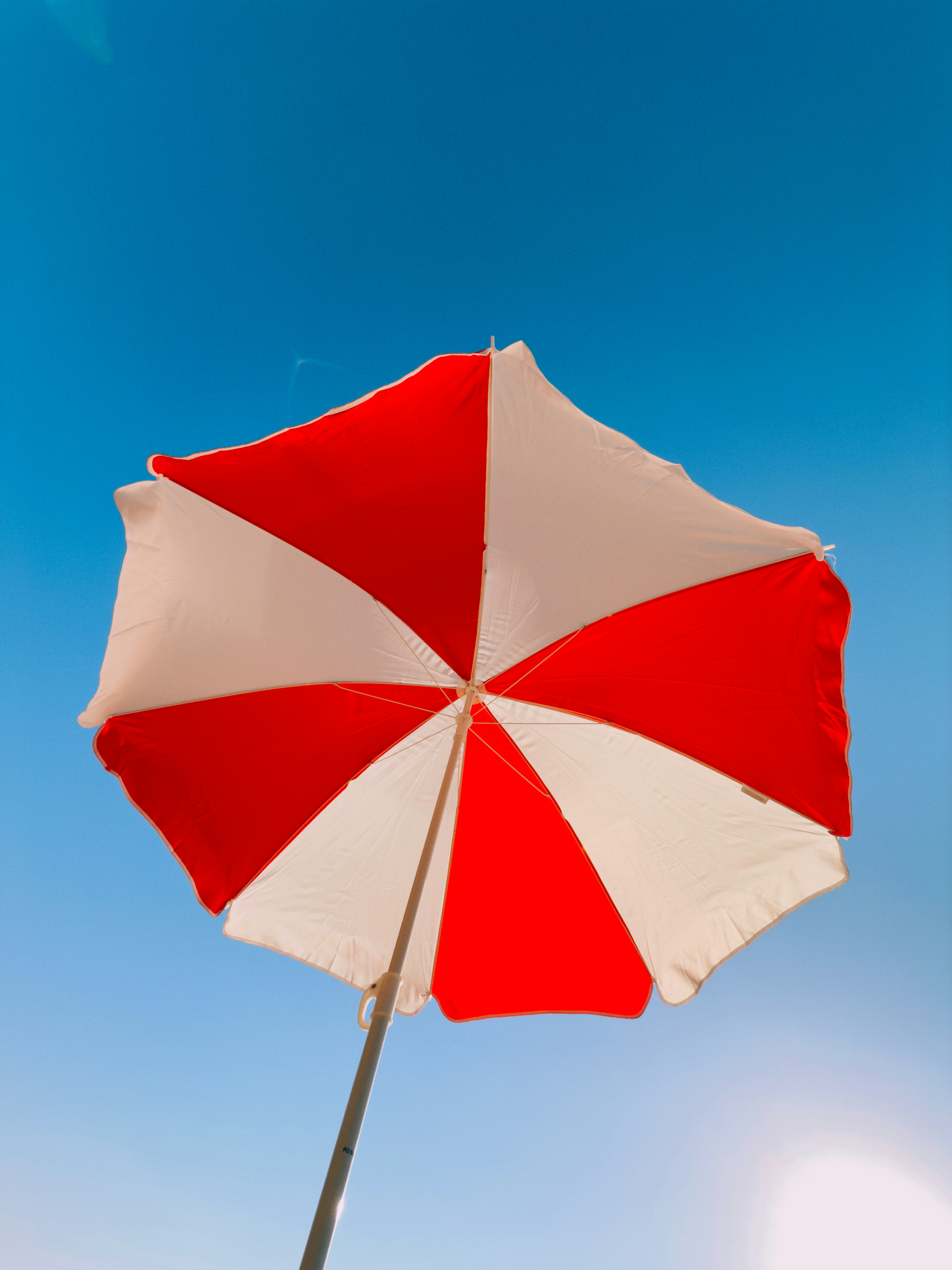 A red and white beach umbrella against a blue sky. photo – Free ...