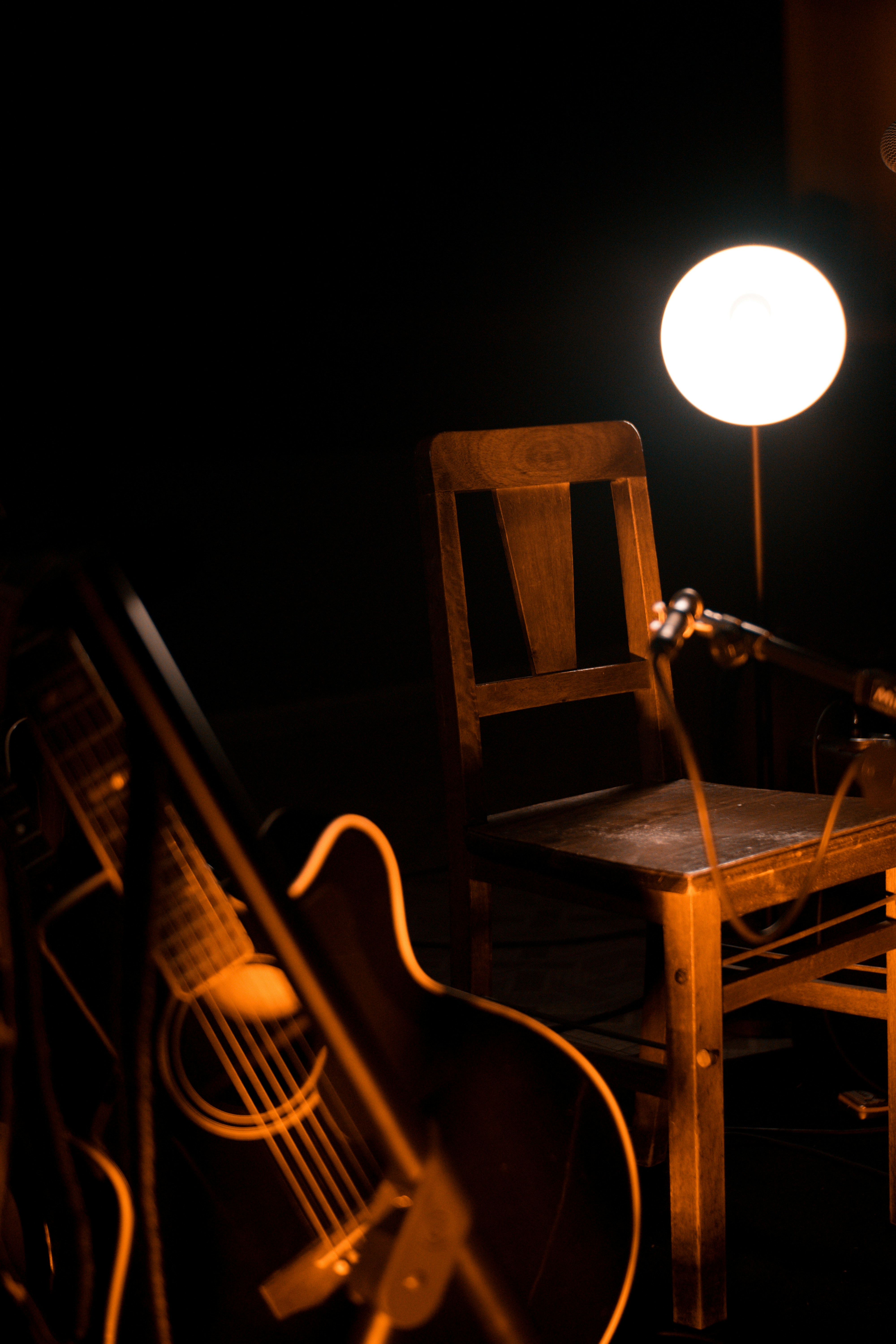 Amber Spotlight on a Lone Studio Chair: Guitar, Microphone, and Quiet Ambience