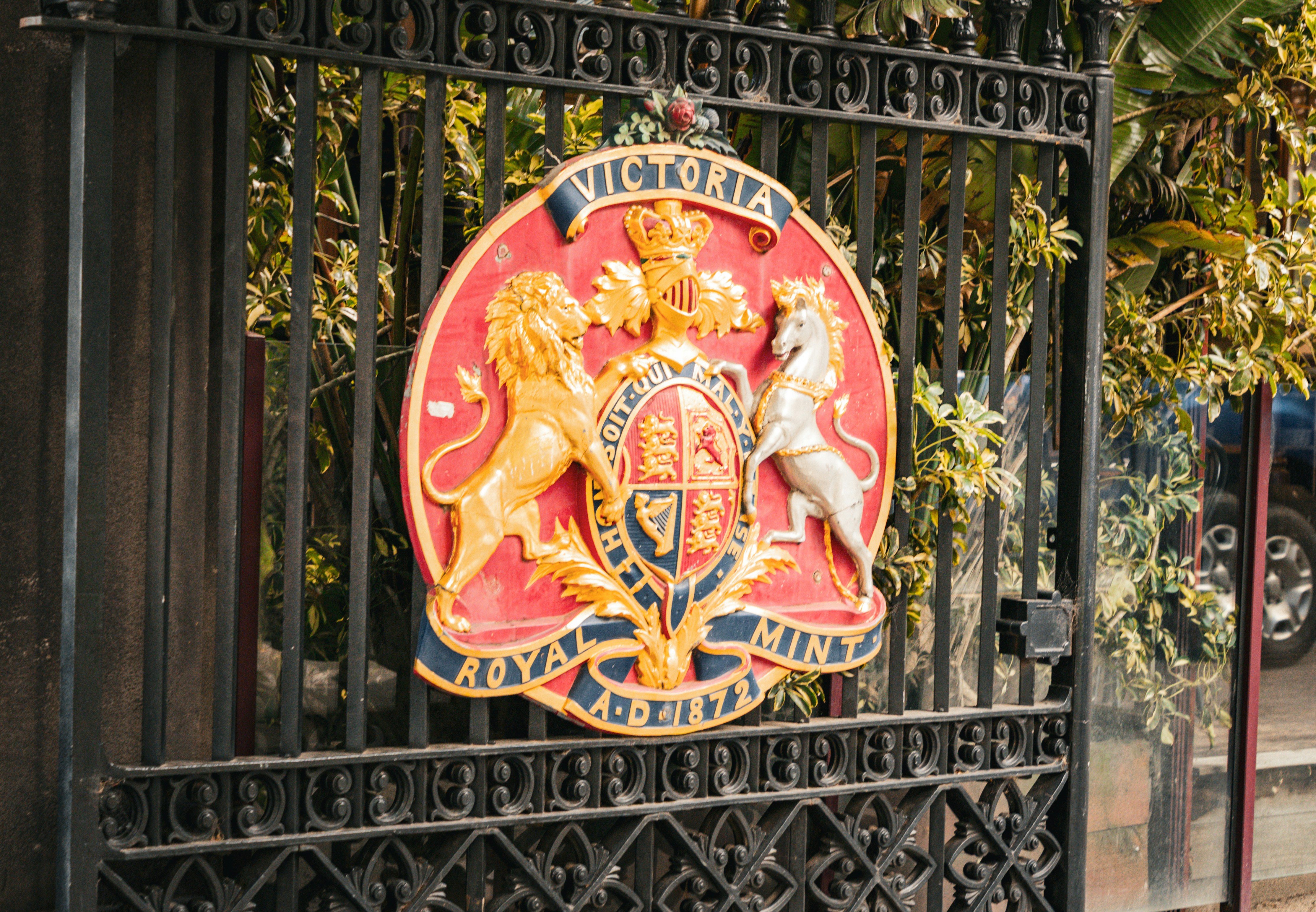 Ornate crest featuring a lion and unicorn on a wrought iron gate adorned with foliage.