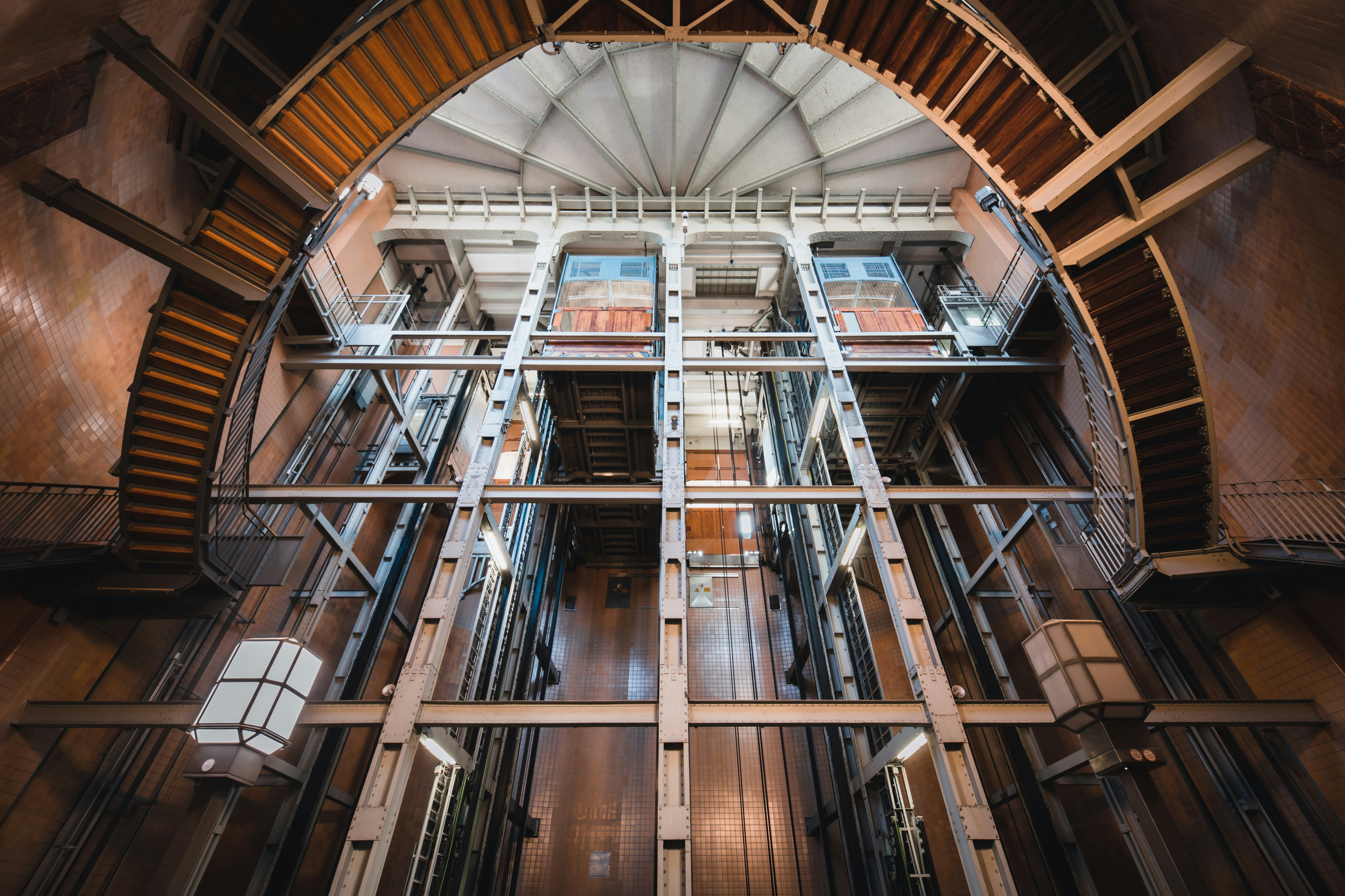Architectural interior with steel structures and staircases forming an intricate pattern under a domed ceiling.