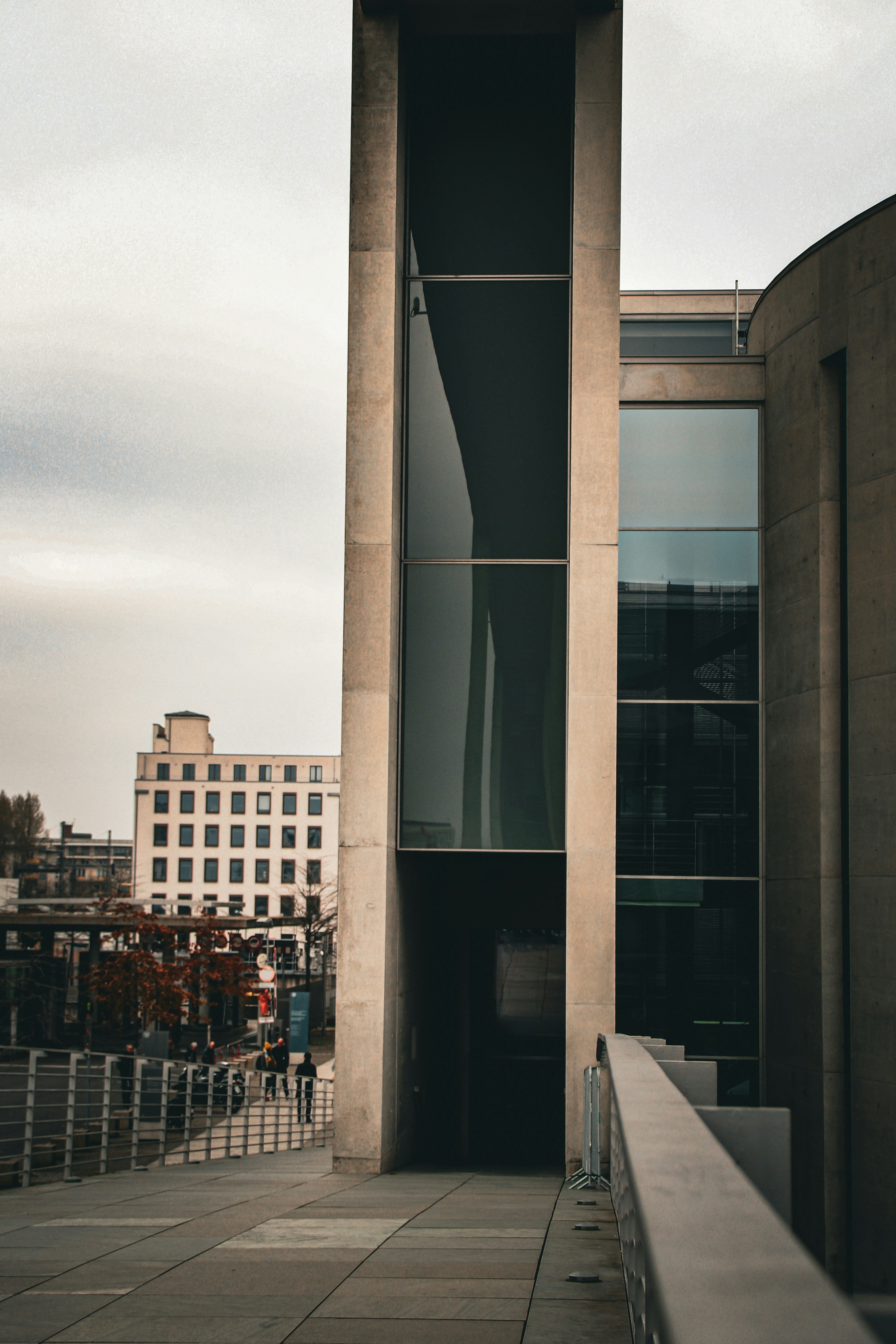 Modern building facade with glass and concrete elements under a cloudy sky.