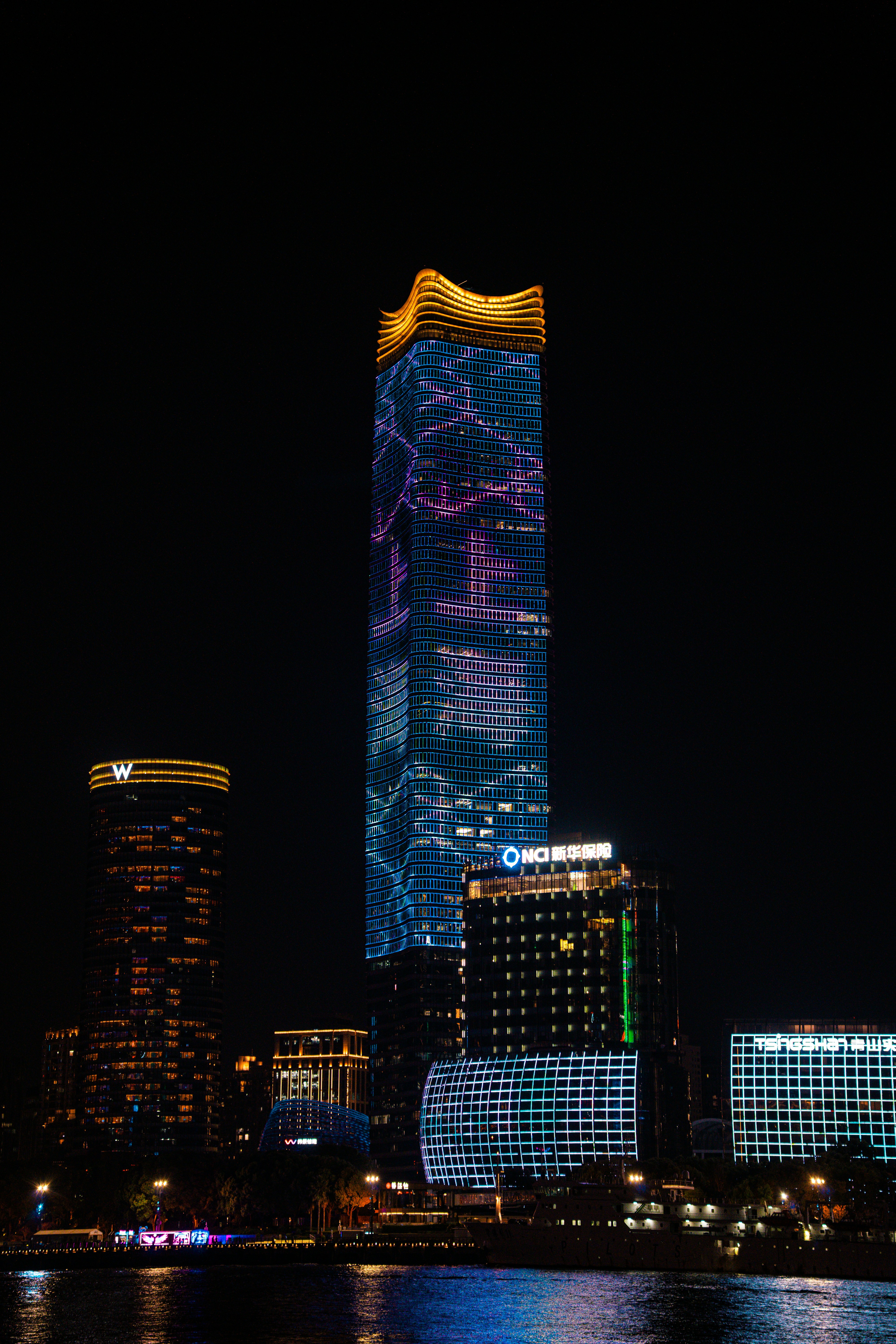 Skyscrapers are illuminated at night over water. photo – Free Travel ...