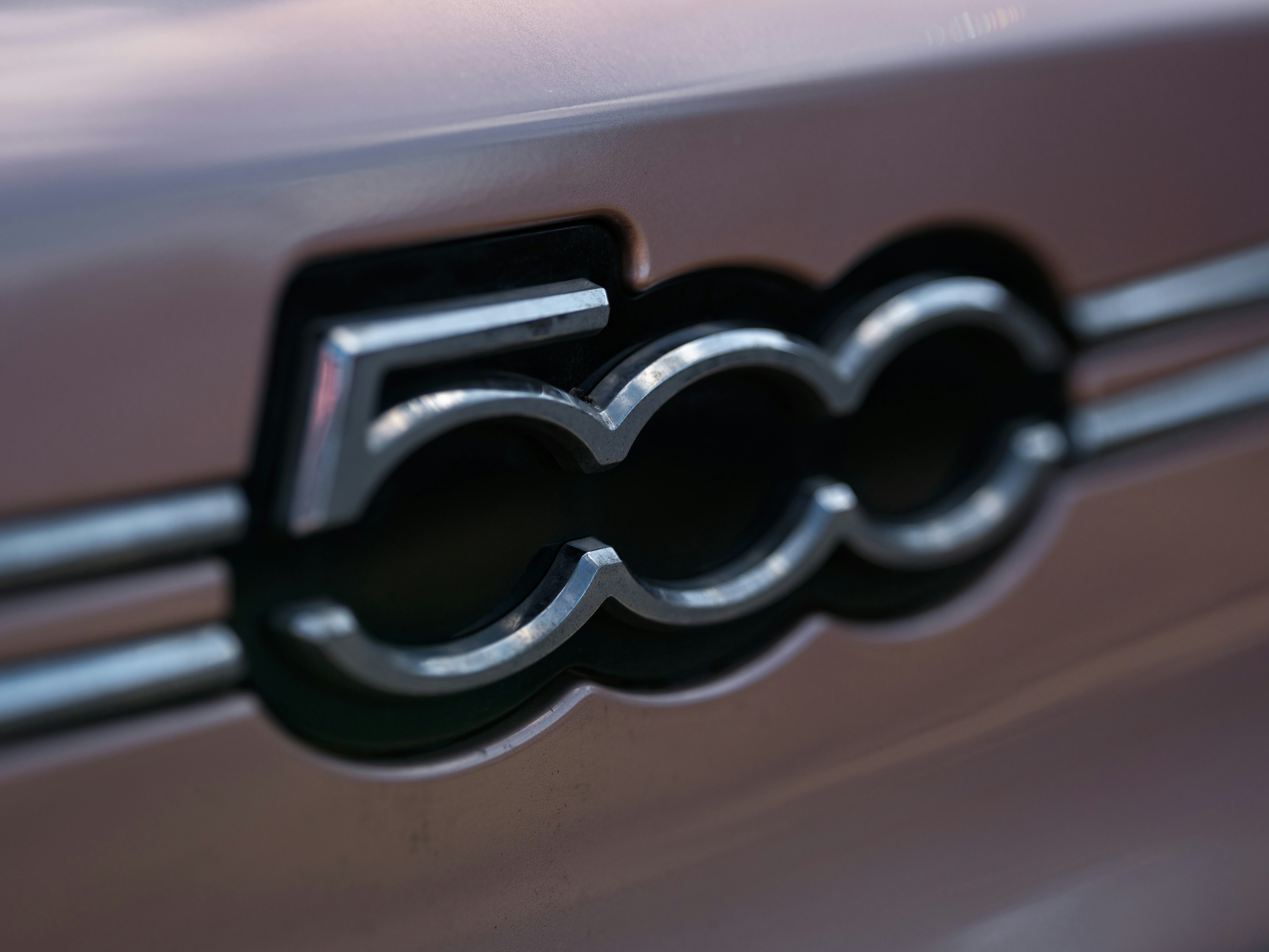 Chrome Rings in a Pastel Frame: Close-Up on the Fiat 500 Badge