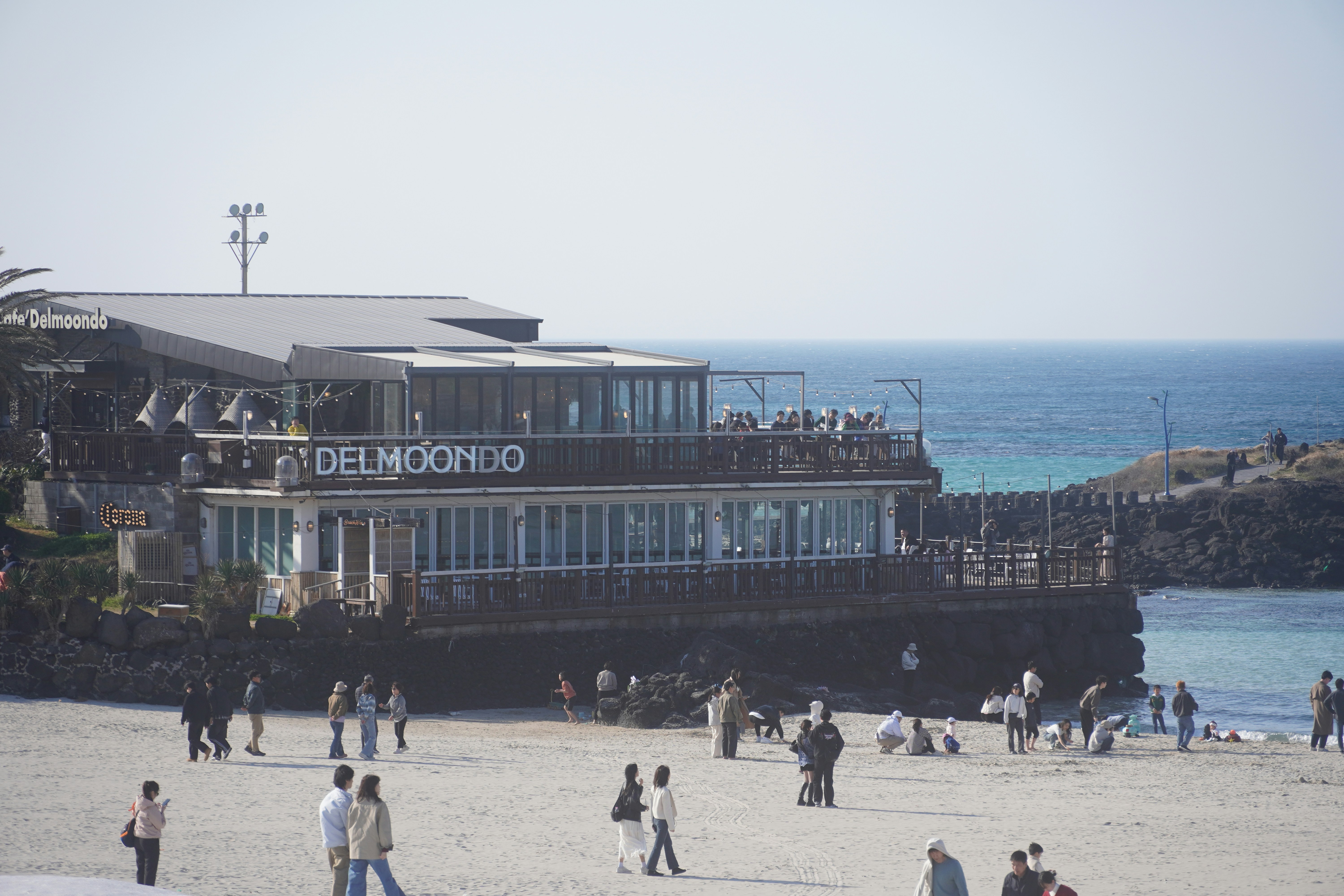 Del Mondo on the Pier: Sunlit Café Overlooking a Bustling Beach