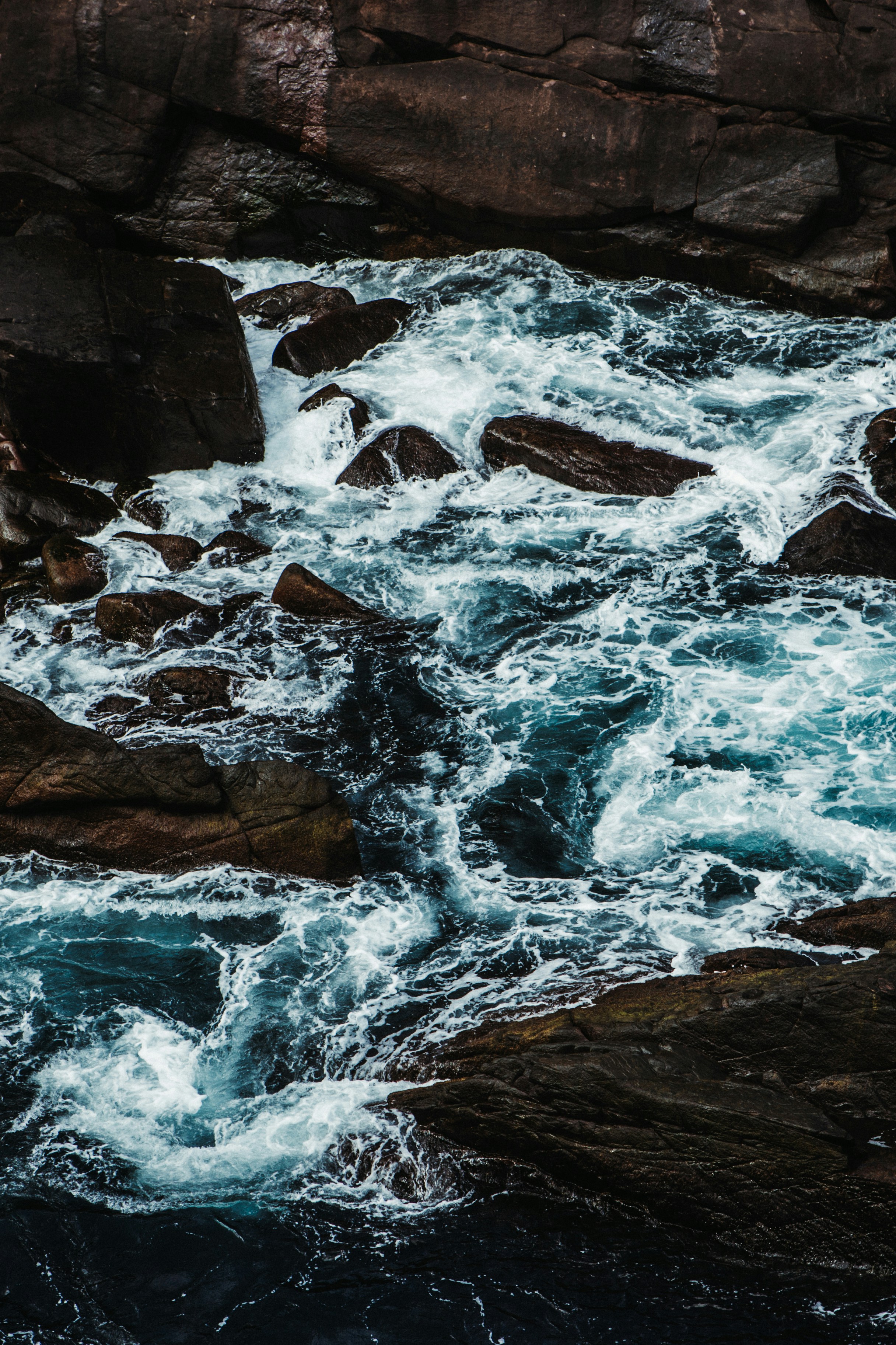 Turbulent water cascading over rugged rocks in a dynamic stream.