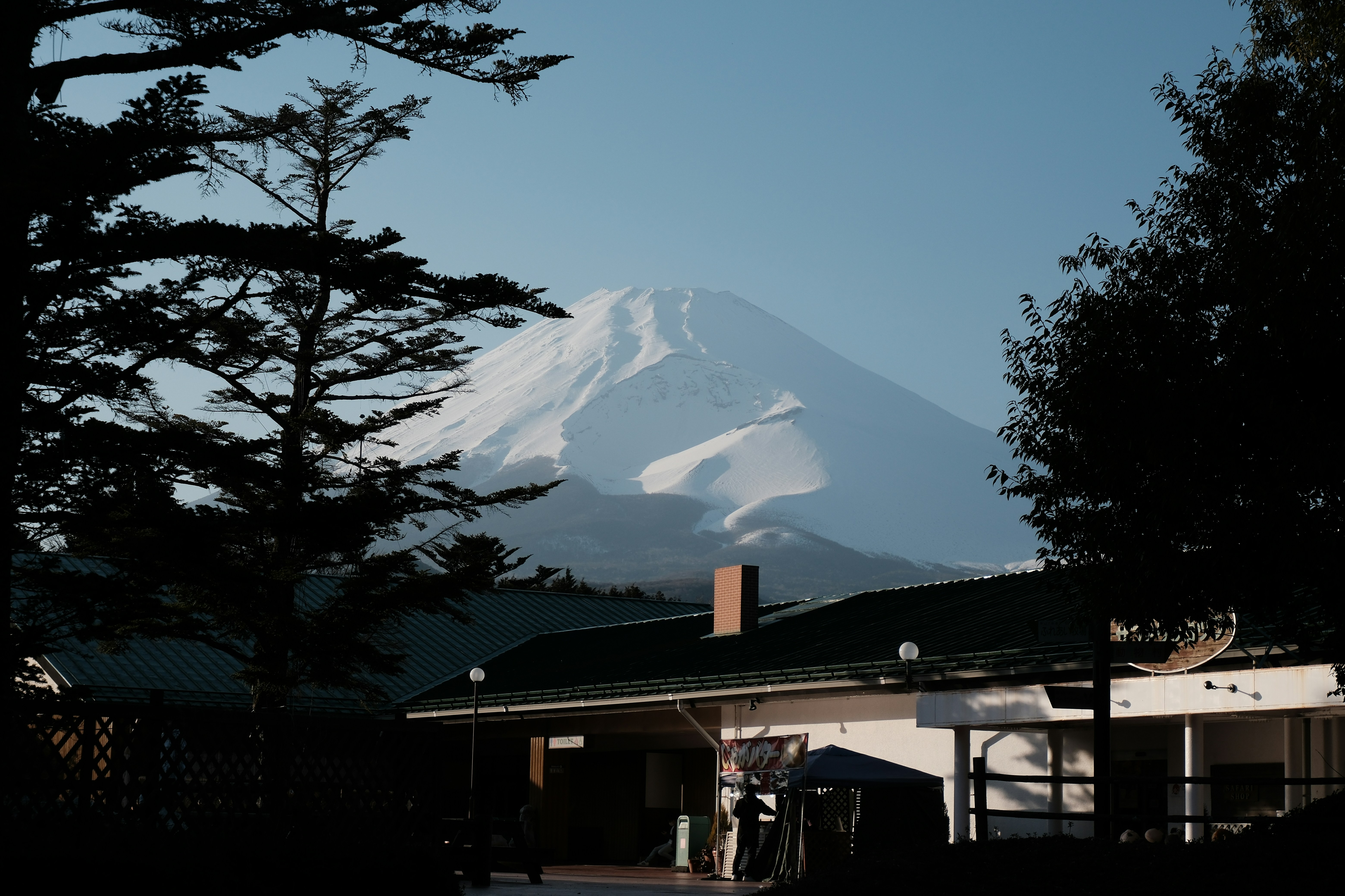 Mount fuji is seen behind a building. photo – Free Human Image on Unsplash